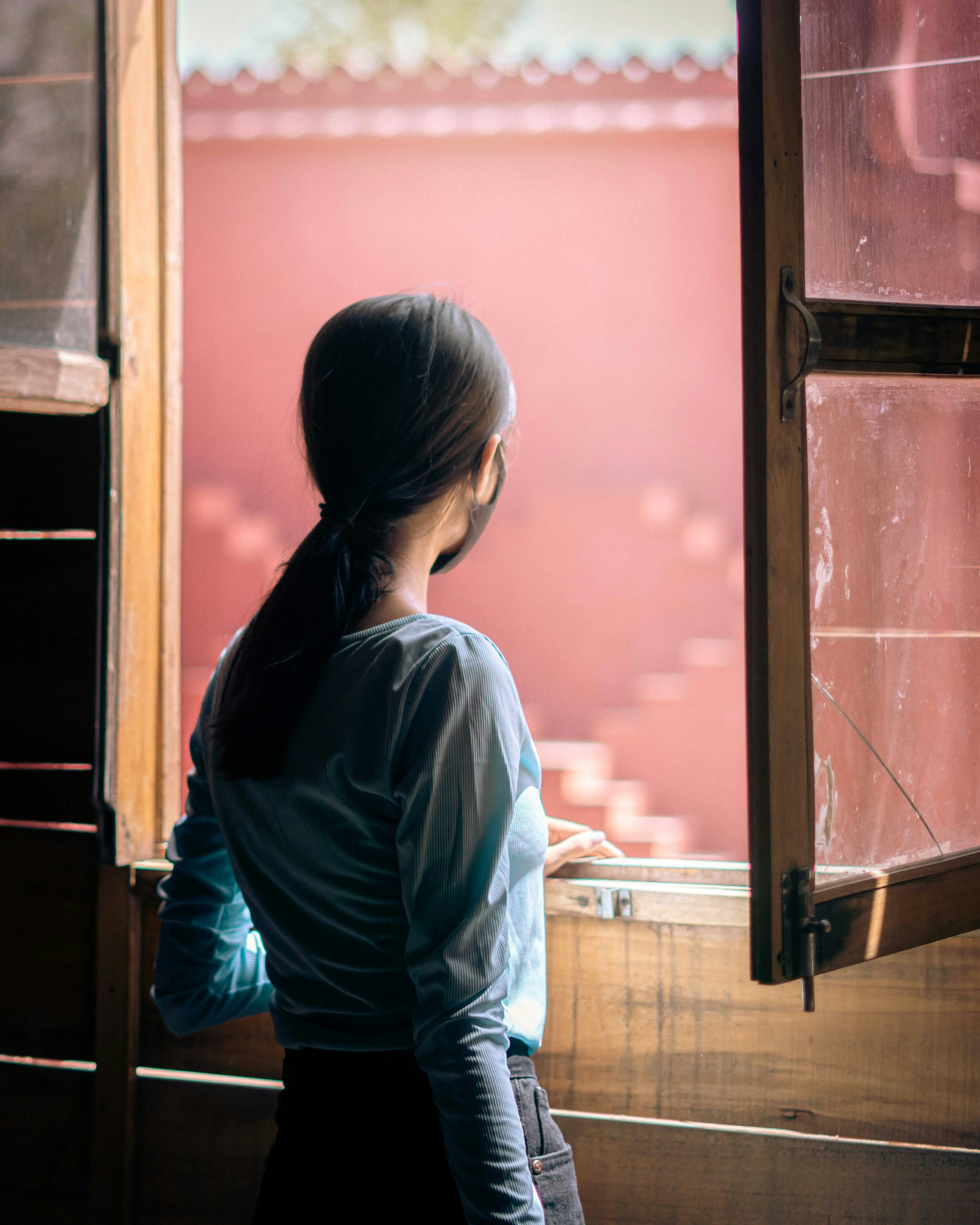 A woman standing in front of a window looking out photo – Free ...