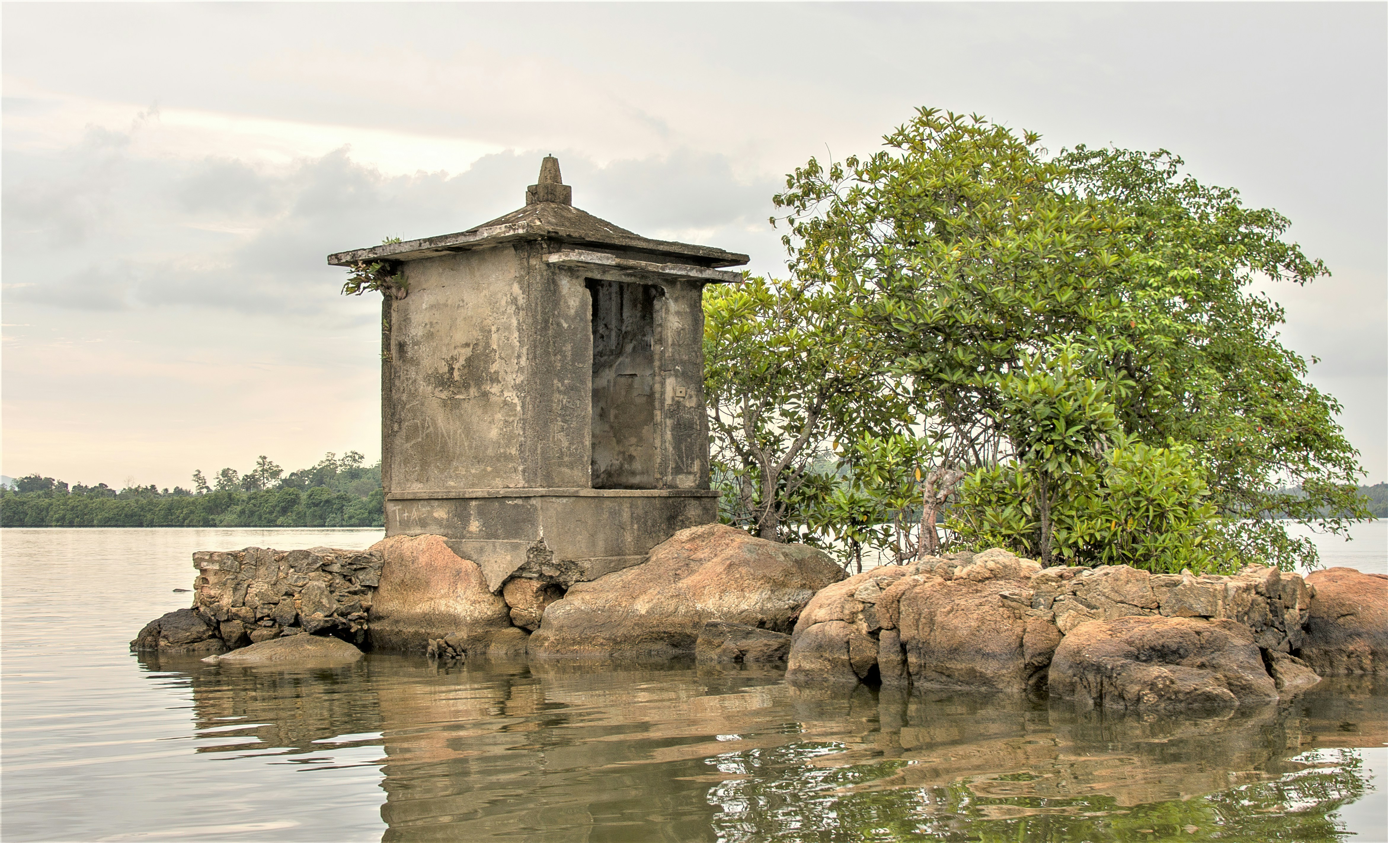 a small tower sitting on top of a rock in the middle of a lake
