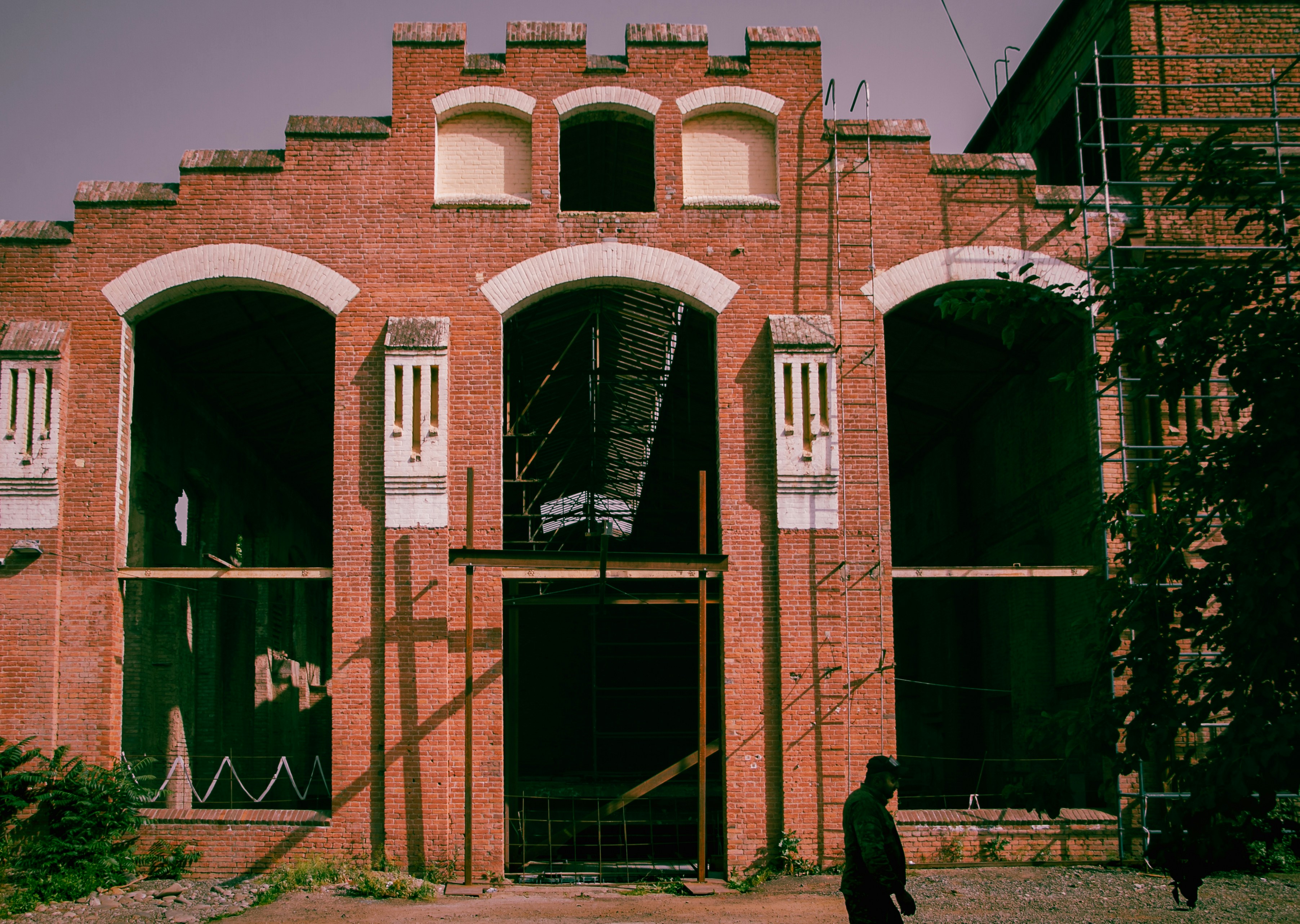 Arched Brickwork Behind Scaffolding: A Quiet Figure on a Construction Day