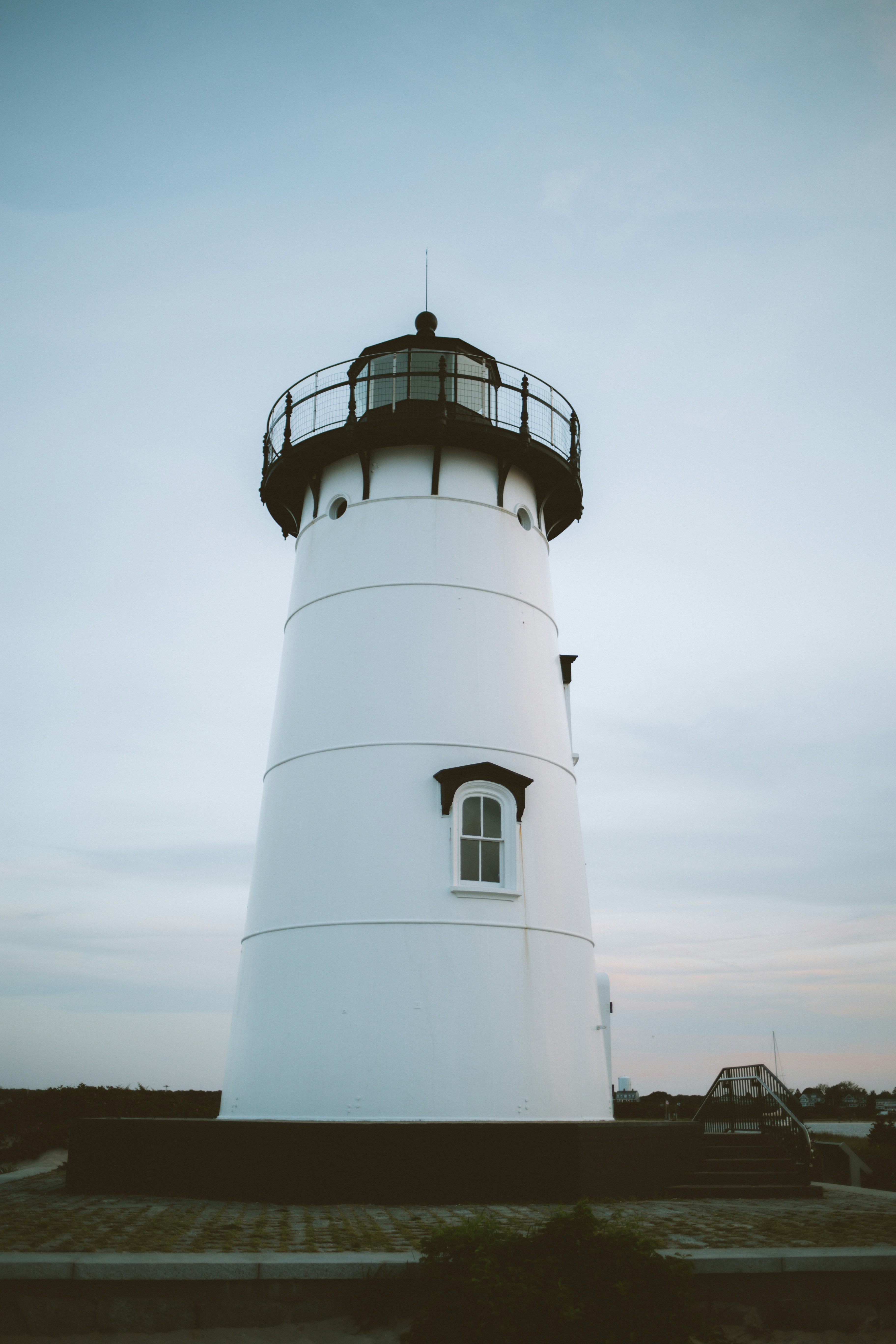 A large white lighthouse sitting on top of a sandy beach photo – Free ...