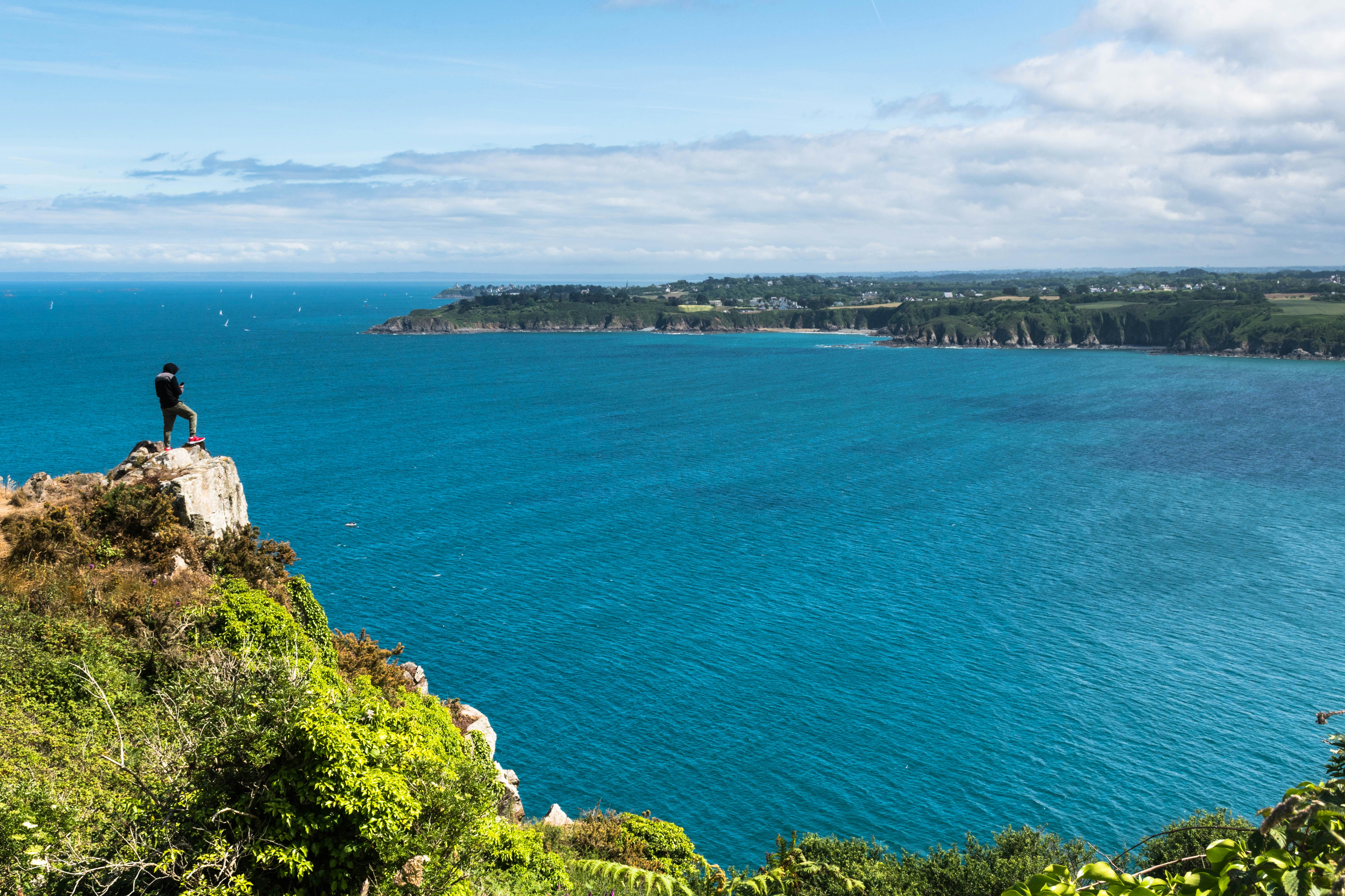 A person standing on a cliff overlooking the ocean photo – Free Pointe ...