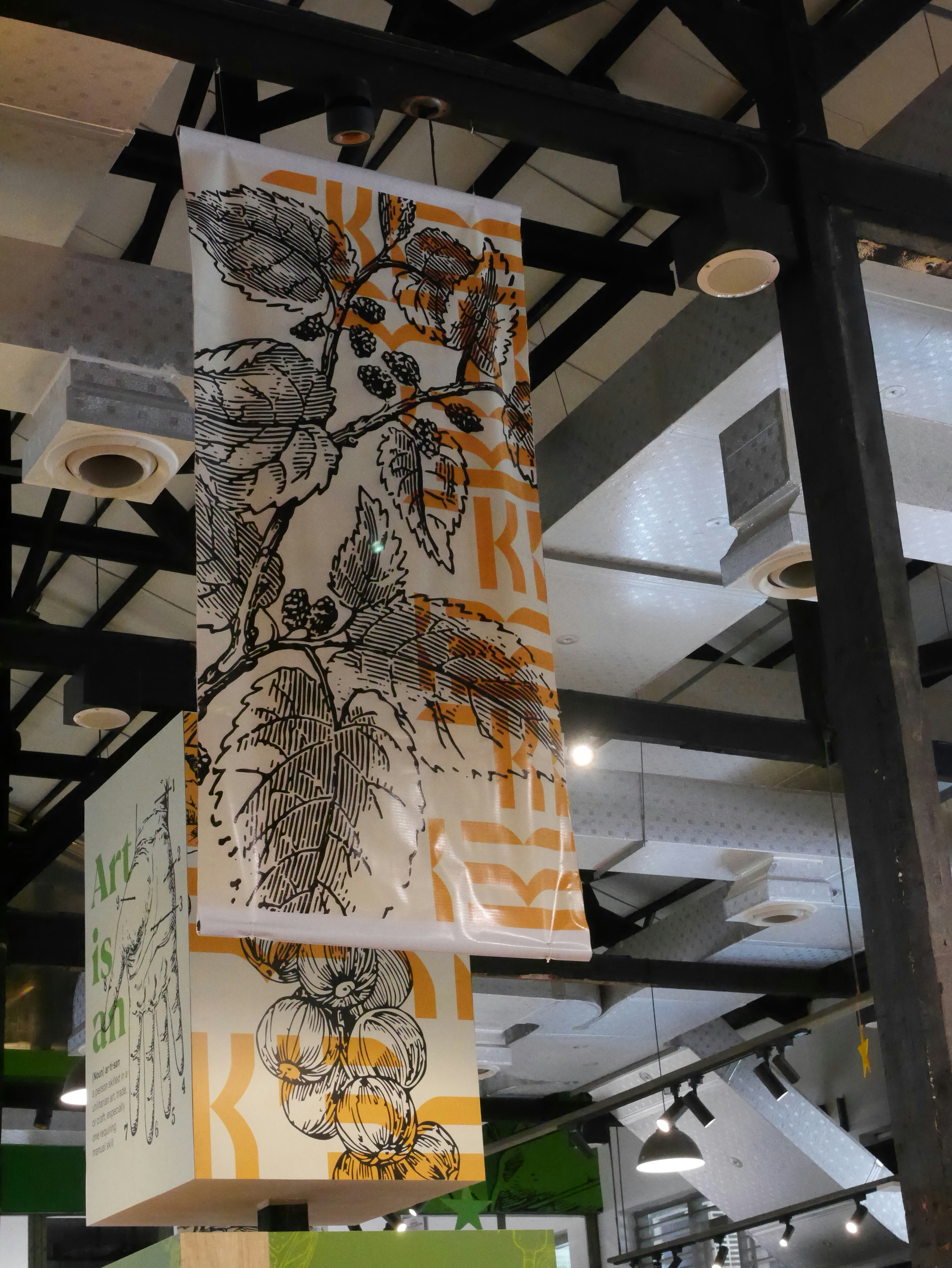 Illustrative banners featuring intricate botanical designs suspended in an industrial space, showcasing a blend of art and nature.