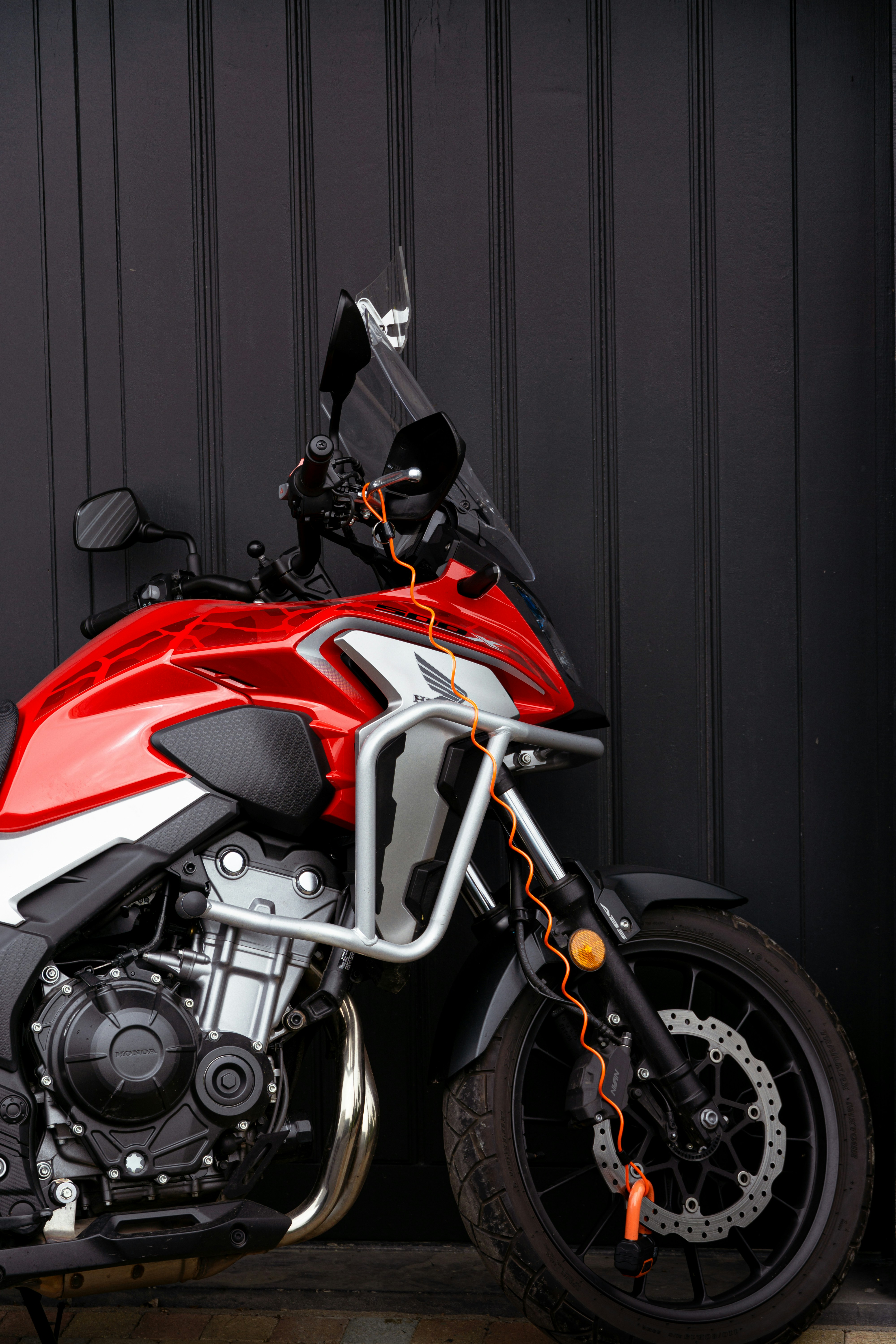 A red and white motorcycle parked next to a black wall photo – Free ...