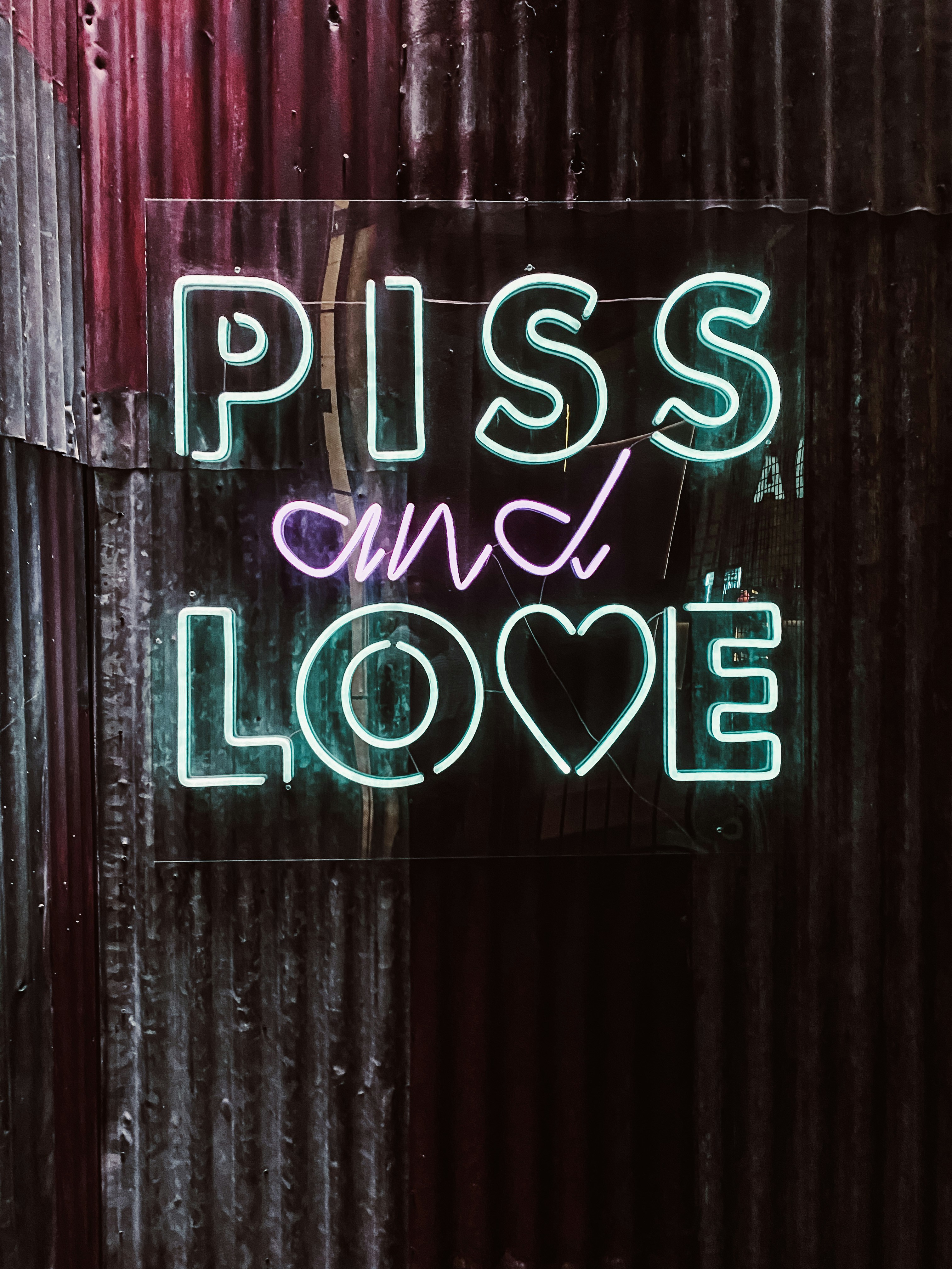 Neon Whispers: PISS and LOVE on Rusted Steel