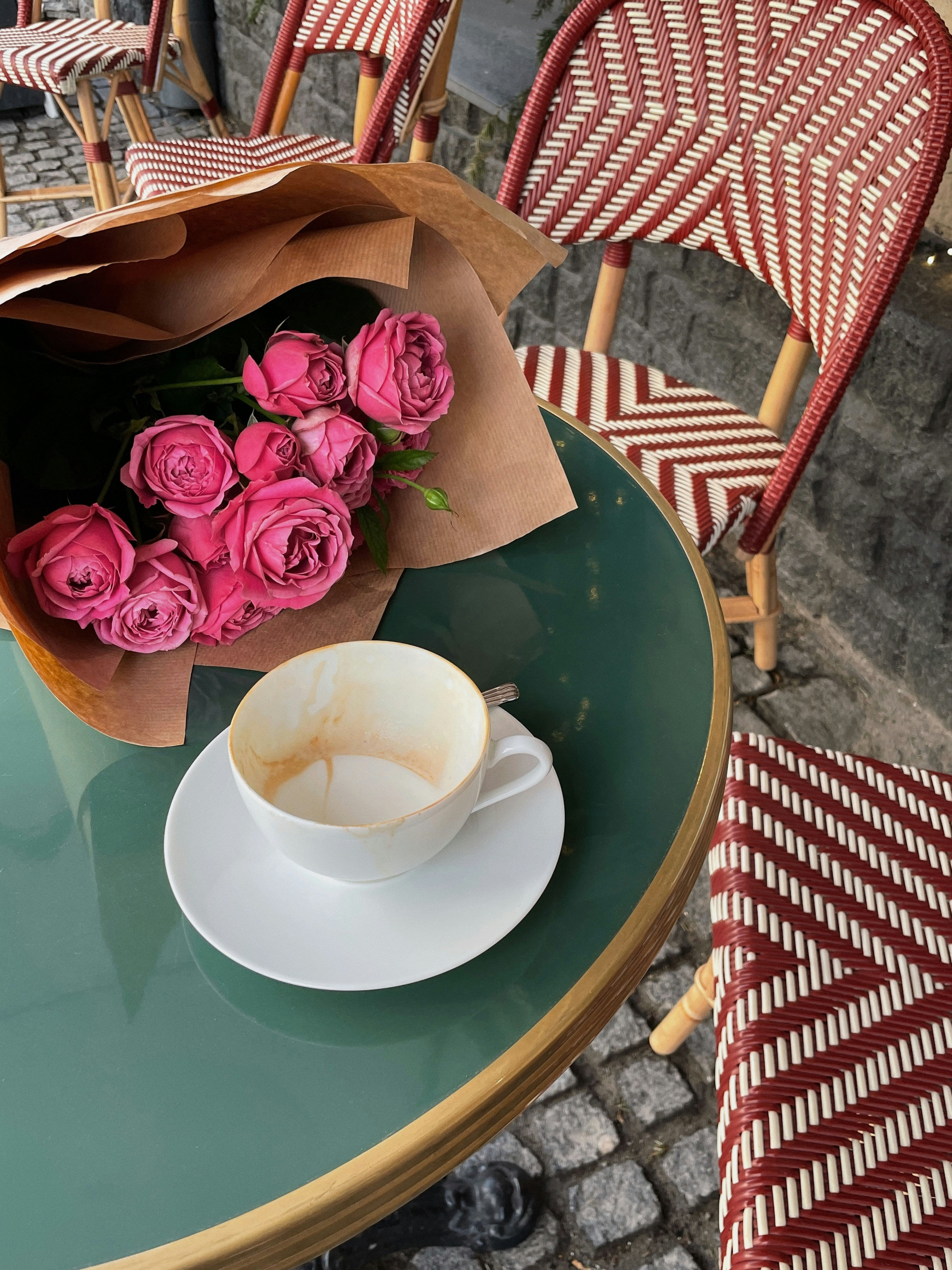 Una taza de té en una mesa verde con sillas y una mesa con una maceta y ...