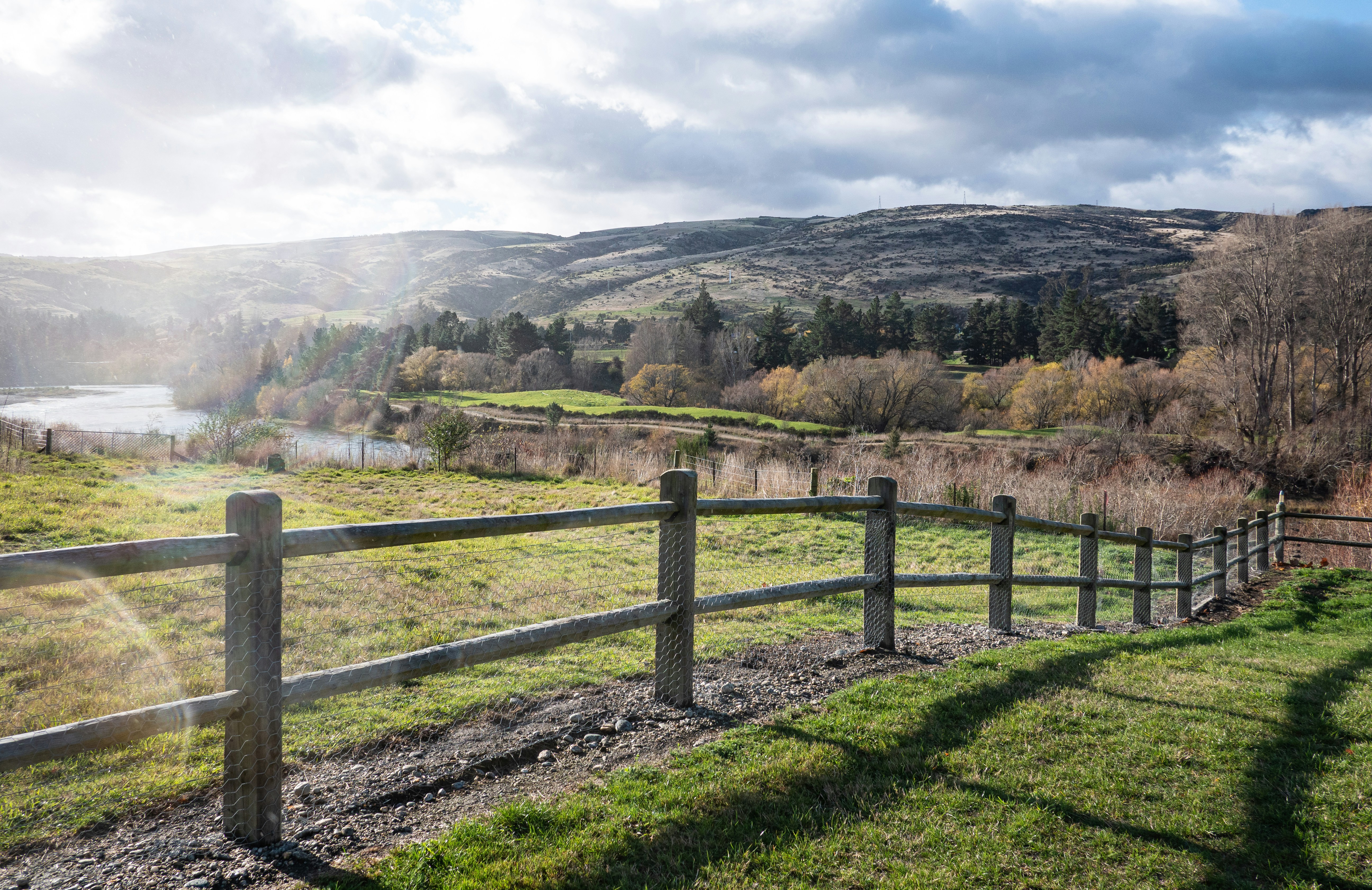 A fenced in field with a lake and mountains in the background photo ...