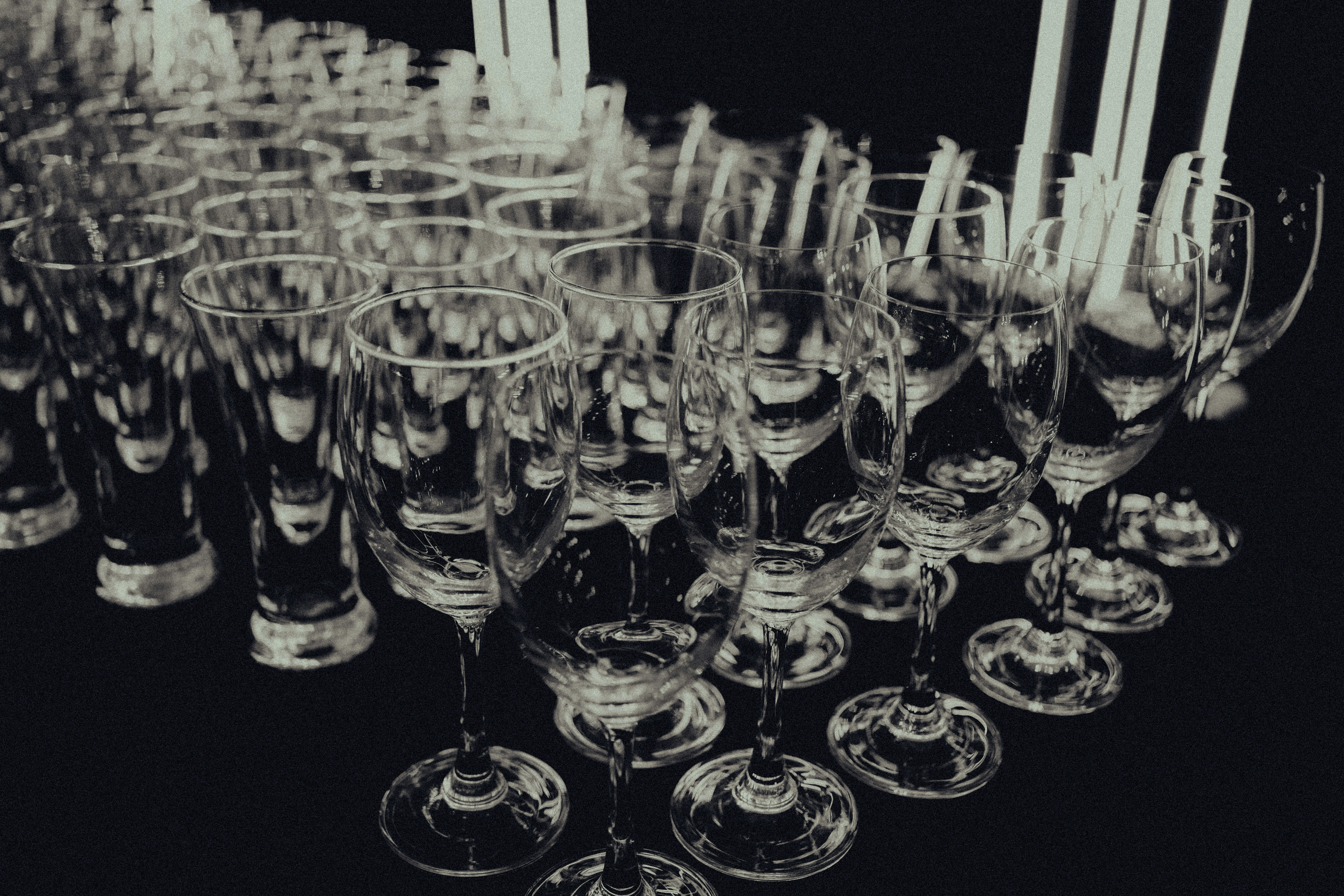 A collection of sparkling glasses arranged in a visually striking pattern, reflecting ambient light against a dark backdrop.