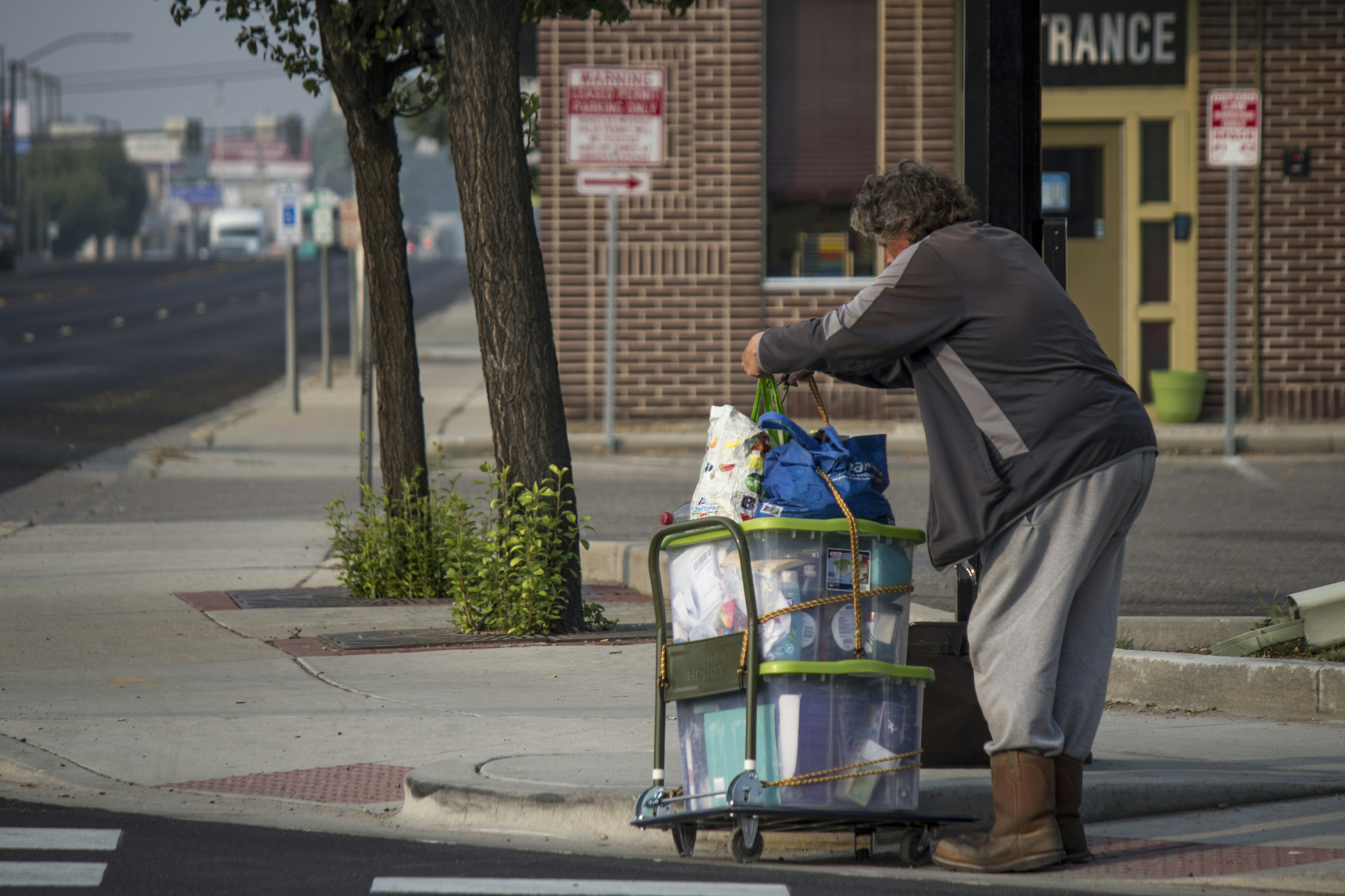 A man pushing a cart full of items on a sidewalk photo – Free Person ...