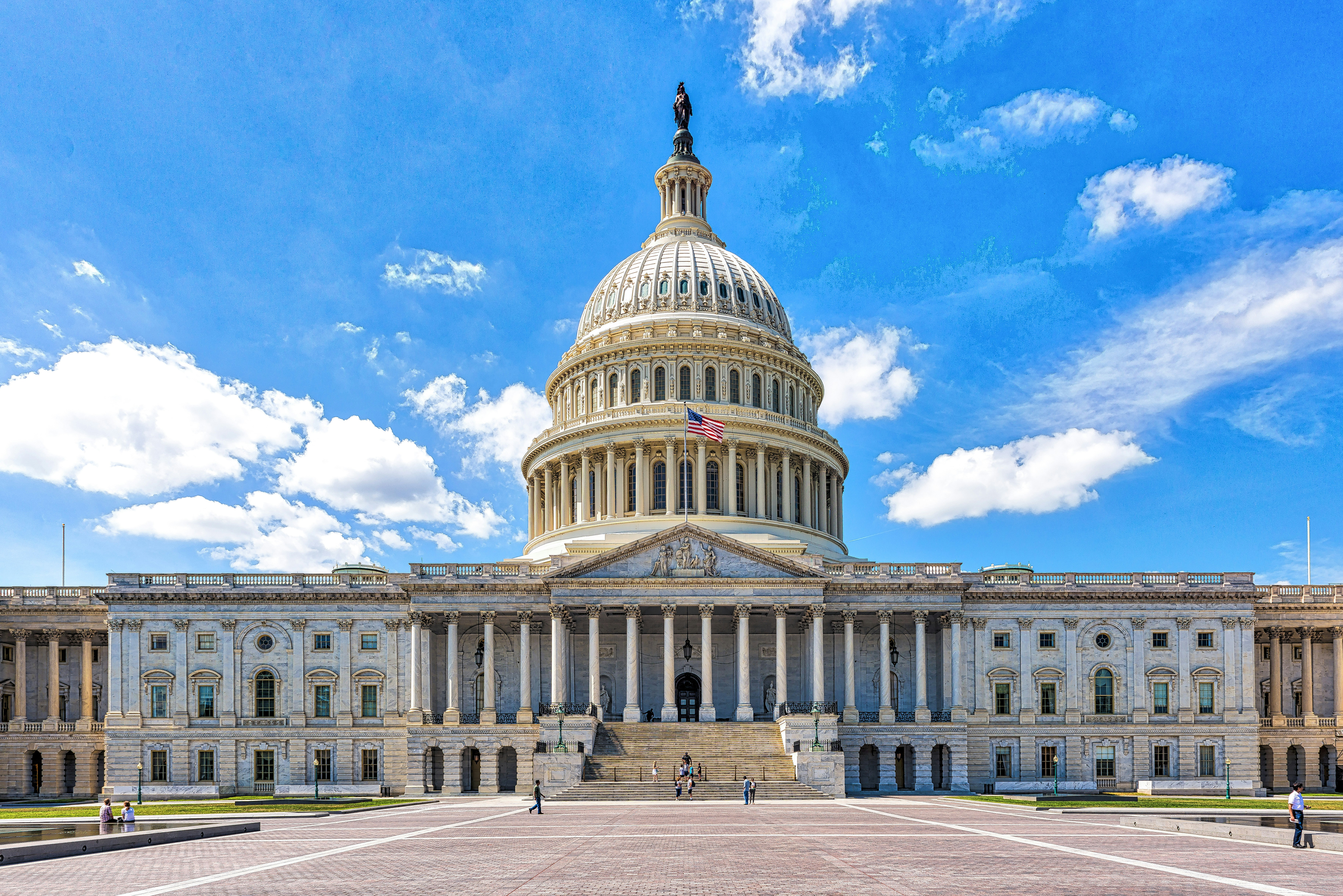 U.S. Capitol building showcasing its iconic dome and neoclassical architecture under a bright blue sky with scattered clouds.