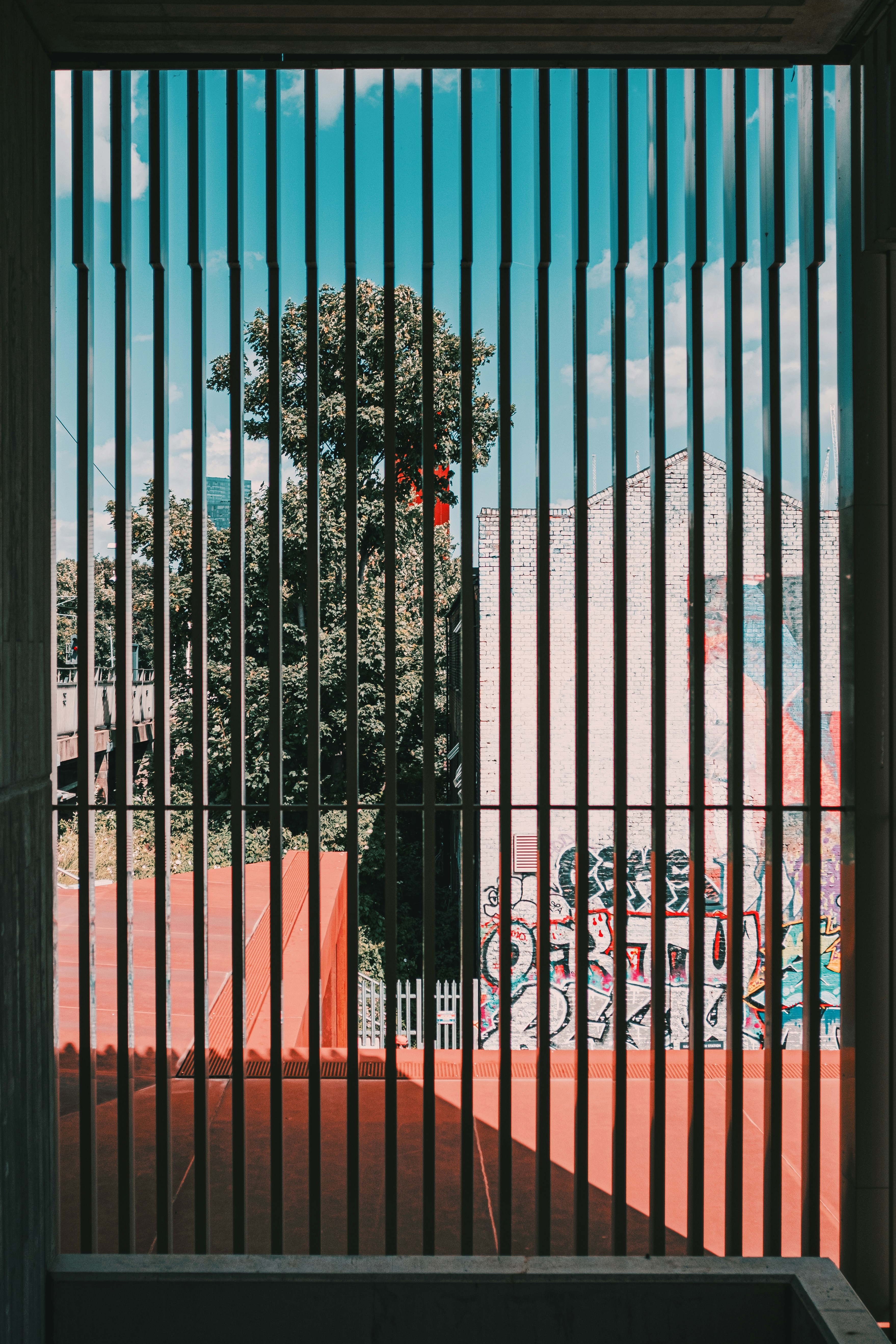 Barred Light: A Sunlit Graffiti Courtyard Framed by Vertical Slats
