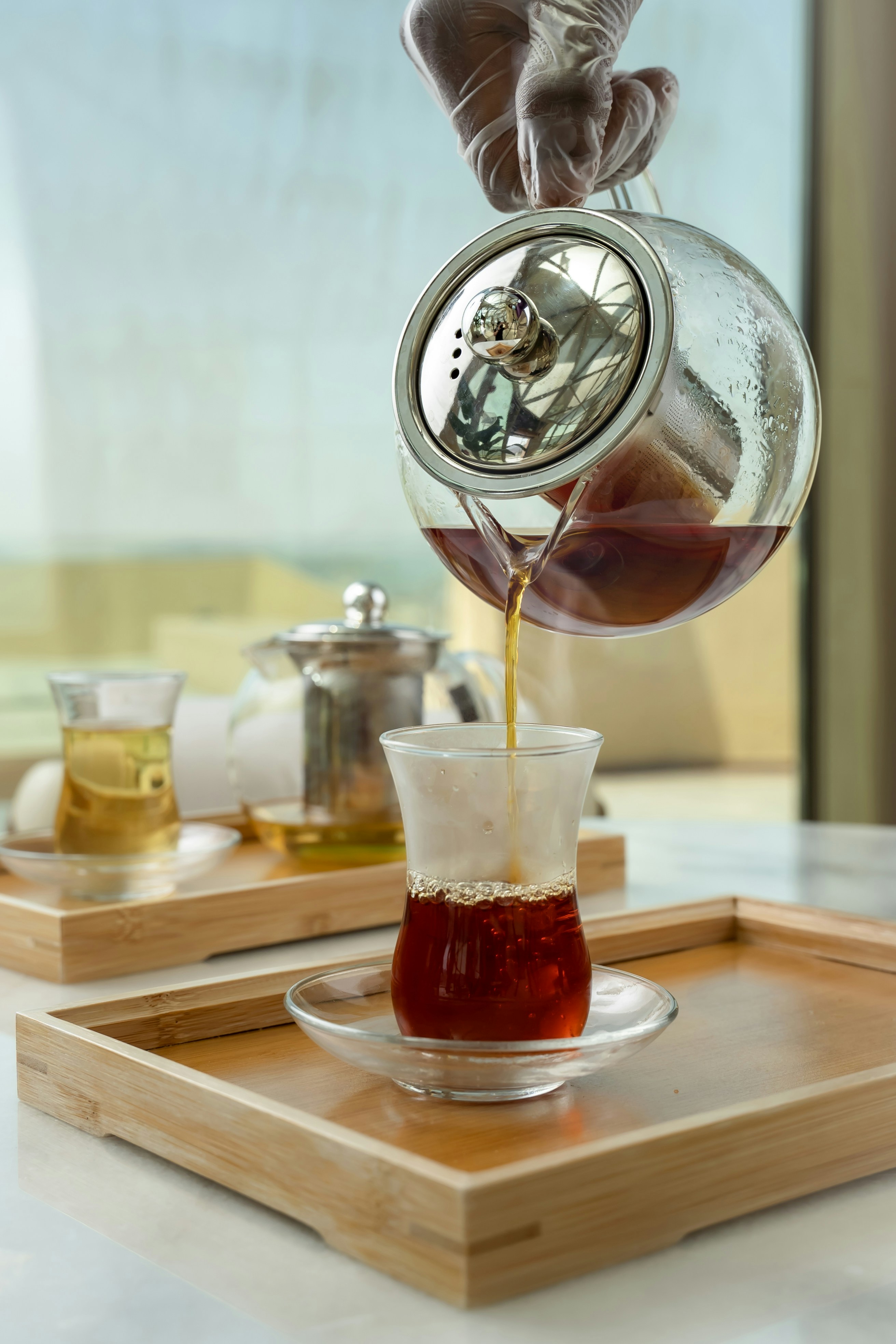 Amber Stream: A Tea Pour into a Glass Cup on a Wooden Tray
