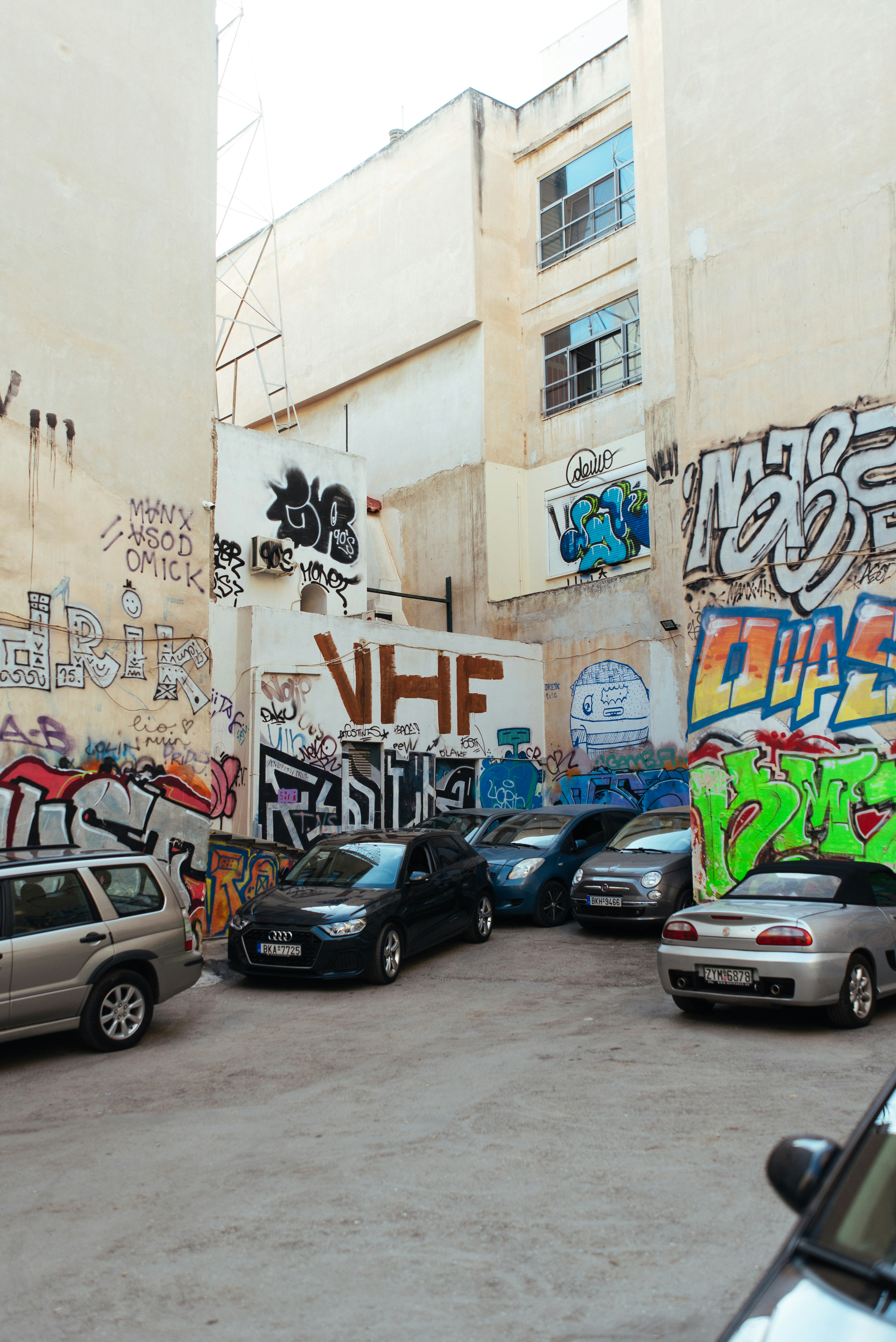 Graffiti Courtyard: A Lineup of Cars Beneath a Kaleidoscopic Wall