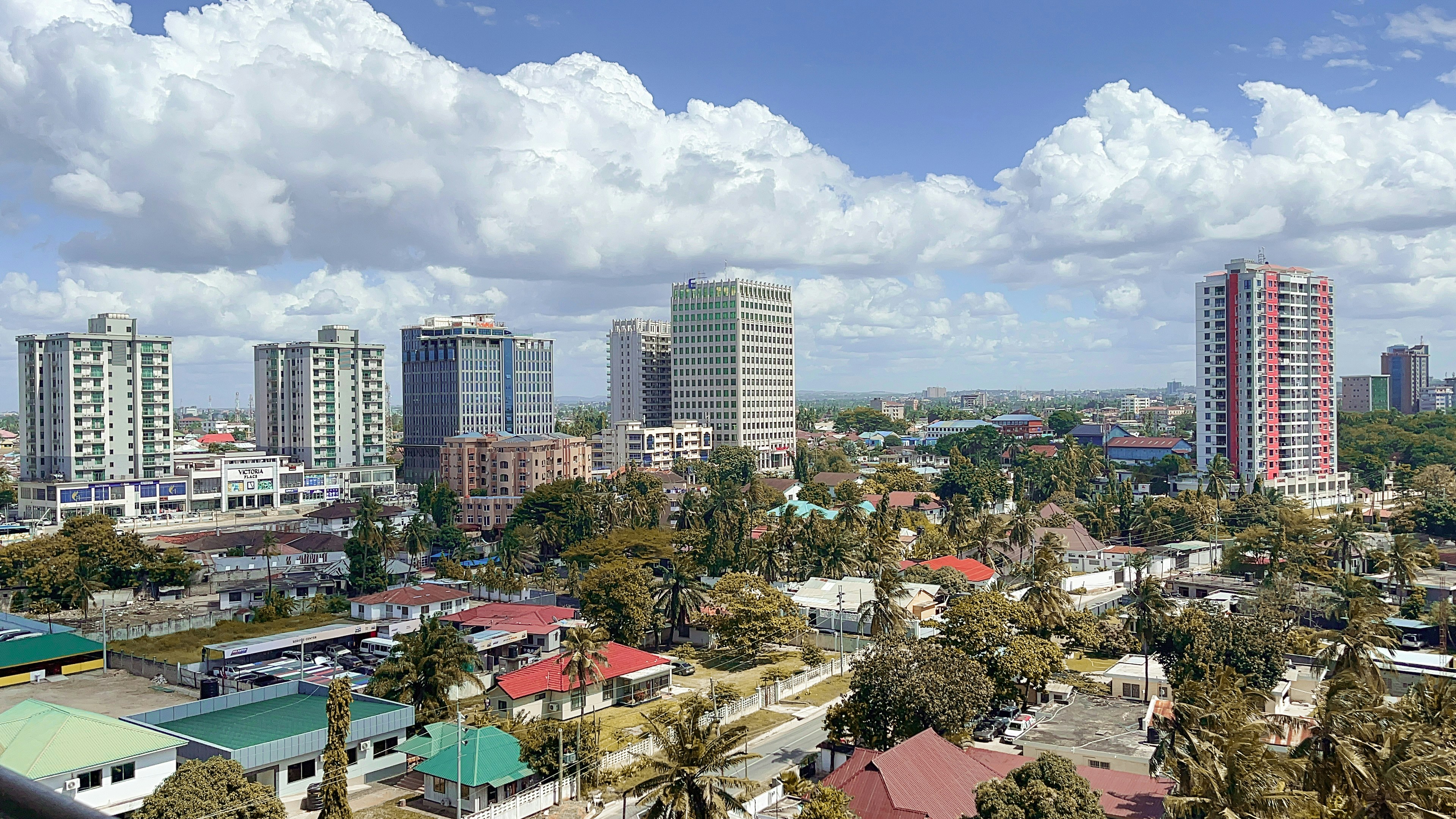 Cityscape with tall buildings under a sky dotted with fluffy clouds.