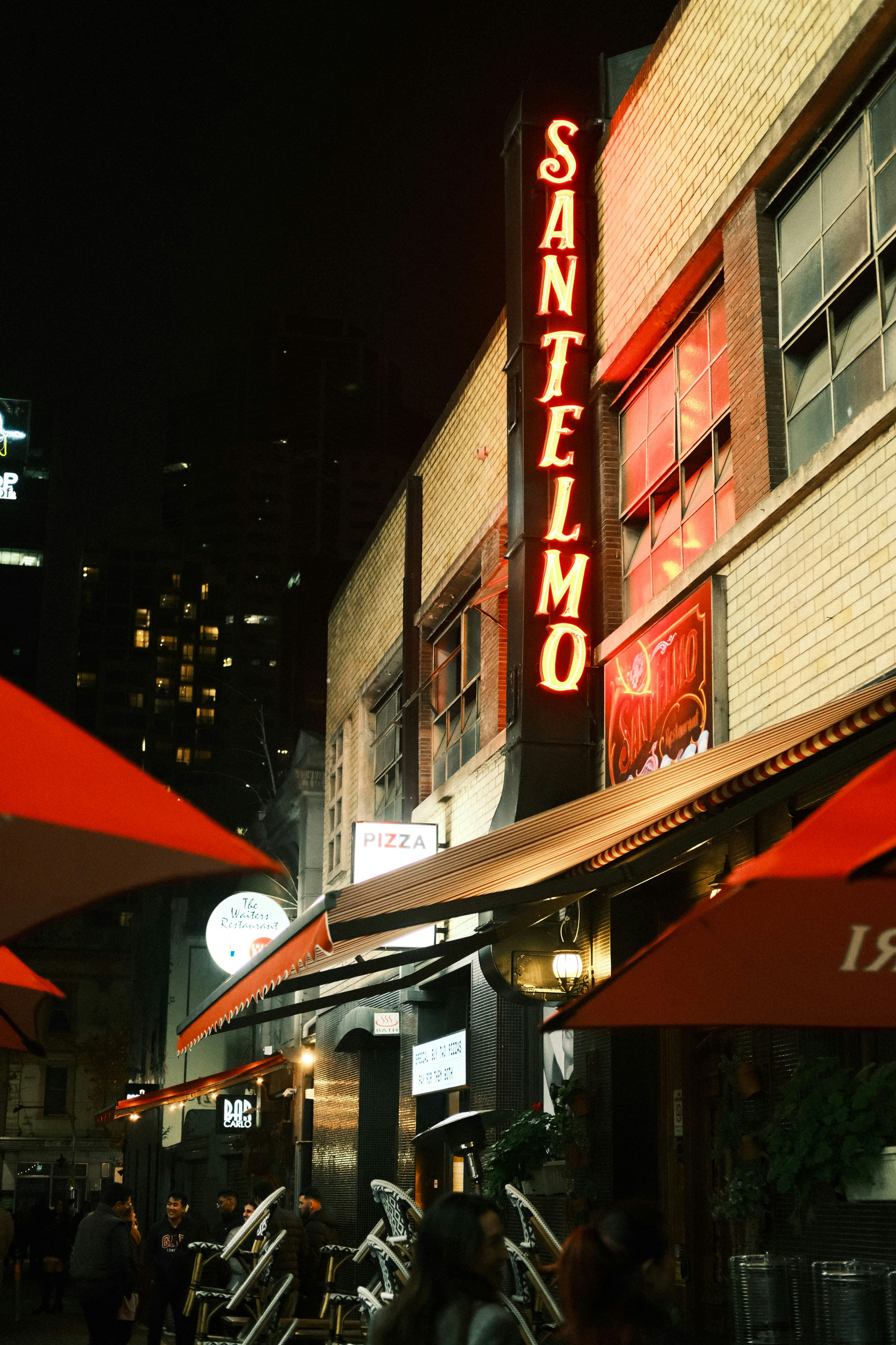 San Telmo Neon Overhang: Nightlife Casts Red on Brick and Umbrellas