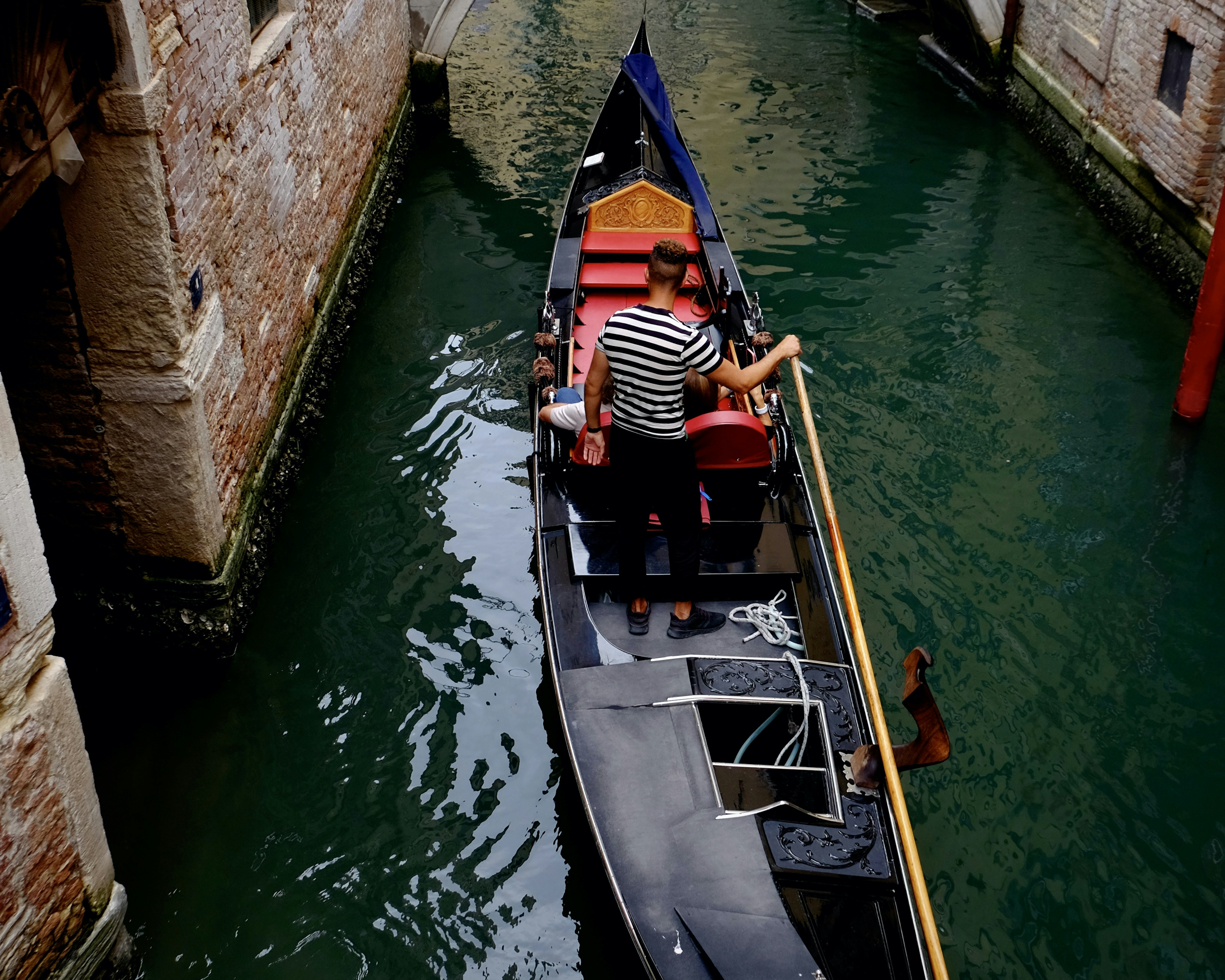 Stripe-Clad Gondolier at the Canal's Edge: Top-Down Venice Moment