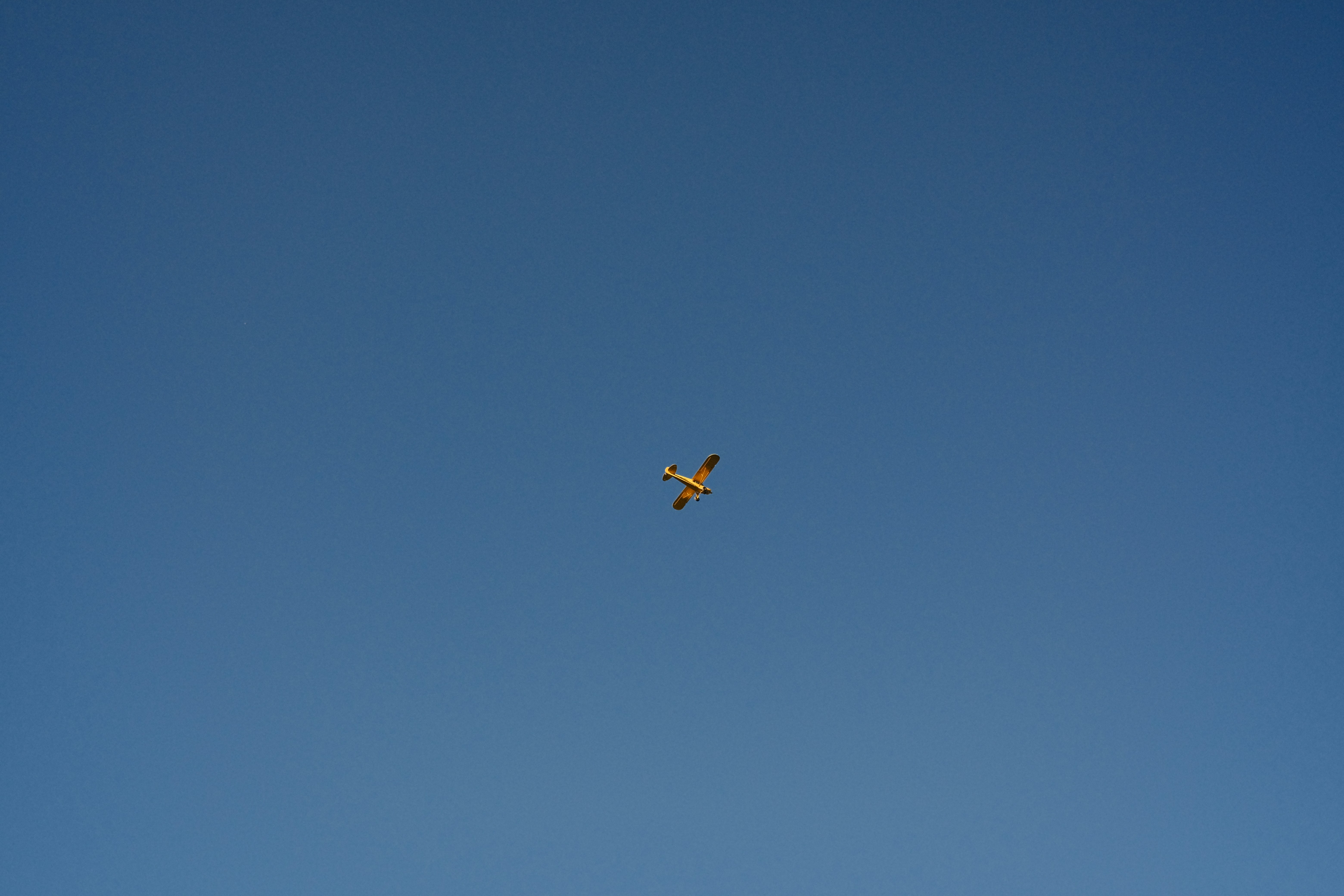 A yellow plane flying in the sky photo – Free Blue Image on Unsplash