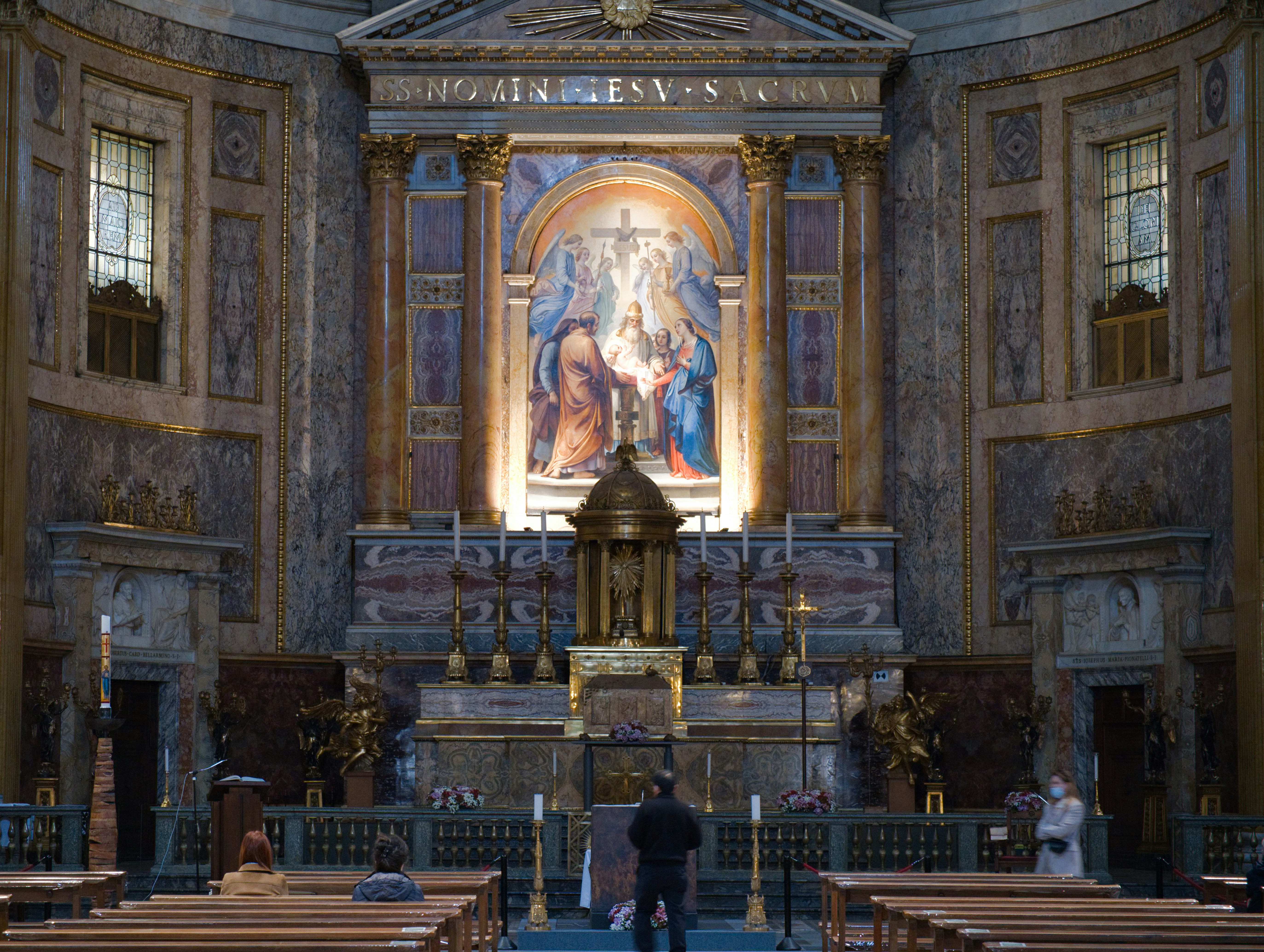 Intricate altar adorned with a vibrant mural depicting a sacred moment, illuminated by soft light in a historic church interior.