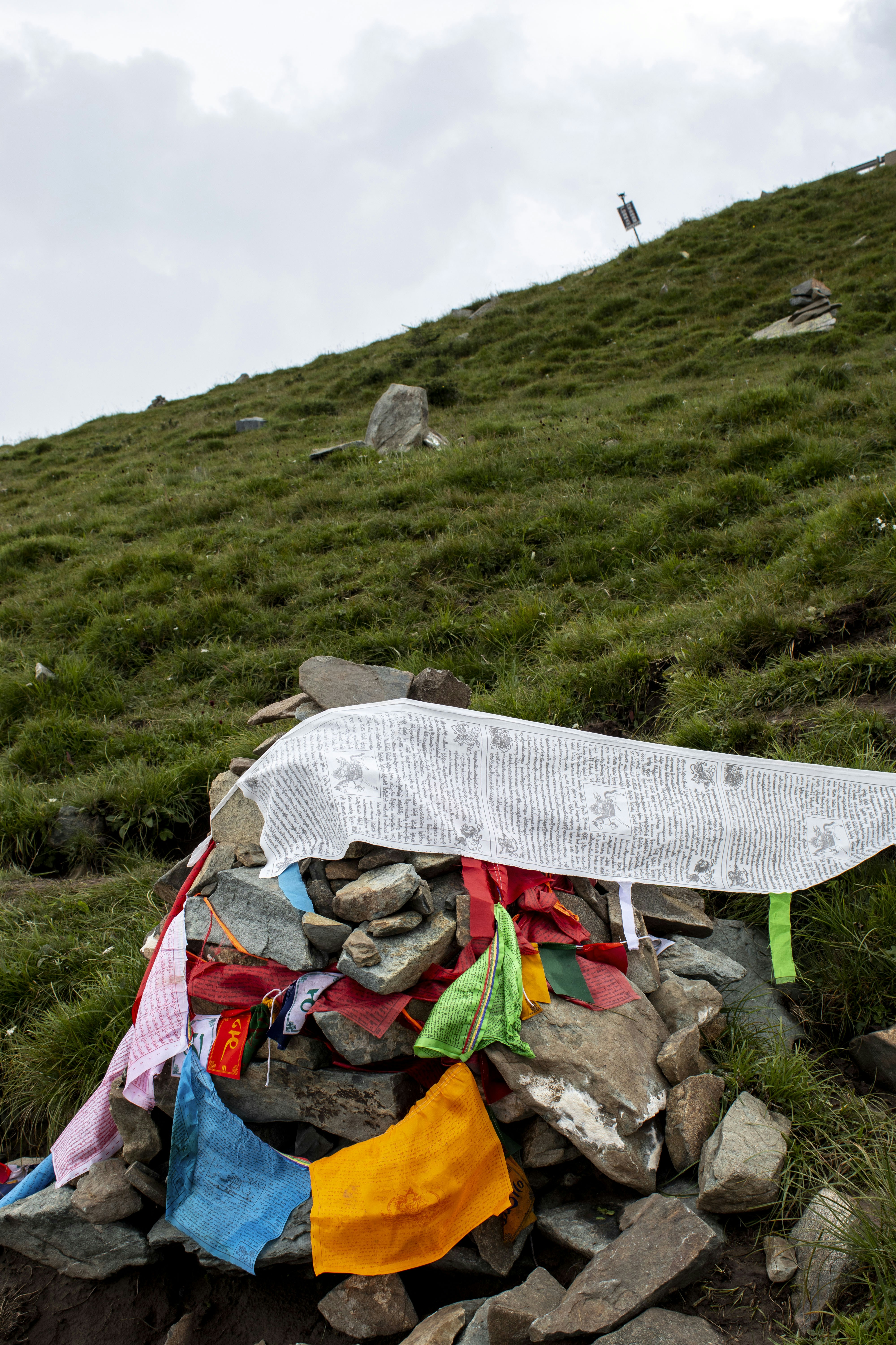 Rock Cairn Shrine with Prayer Flags on Grassy Slope