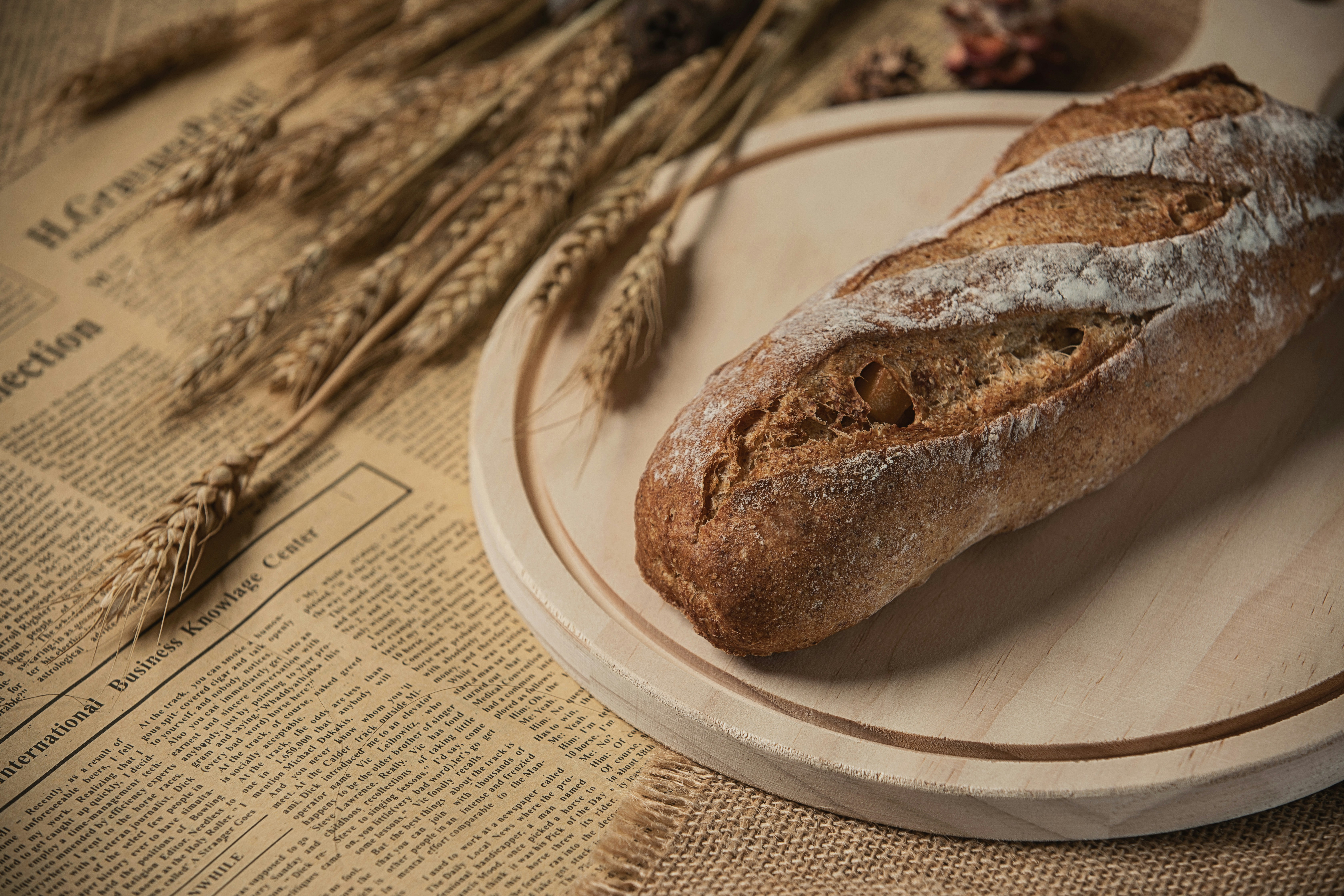 Crust on a Circular Stage: Rustic loaf among wheat and newsprint