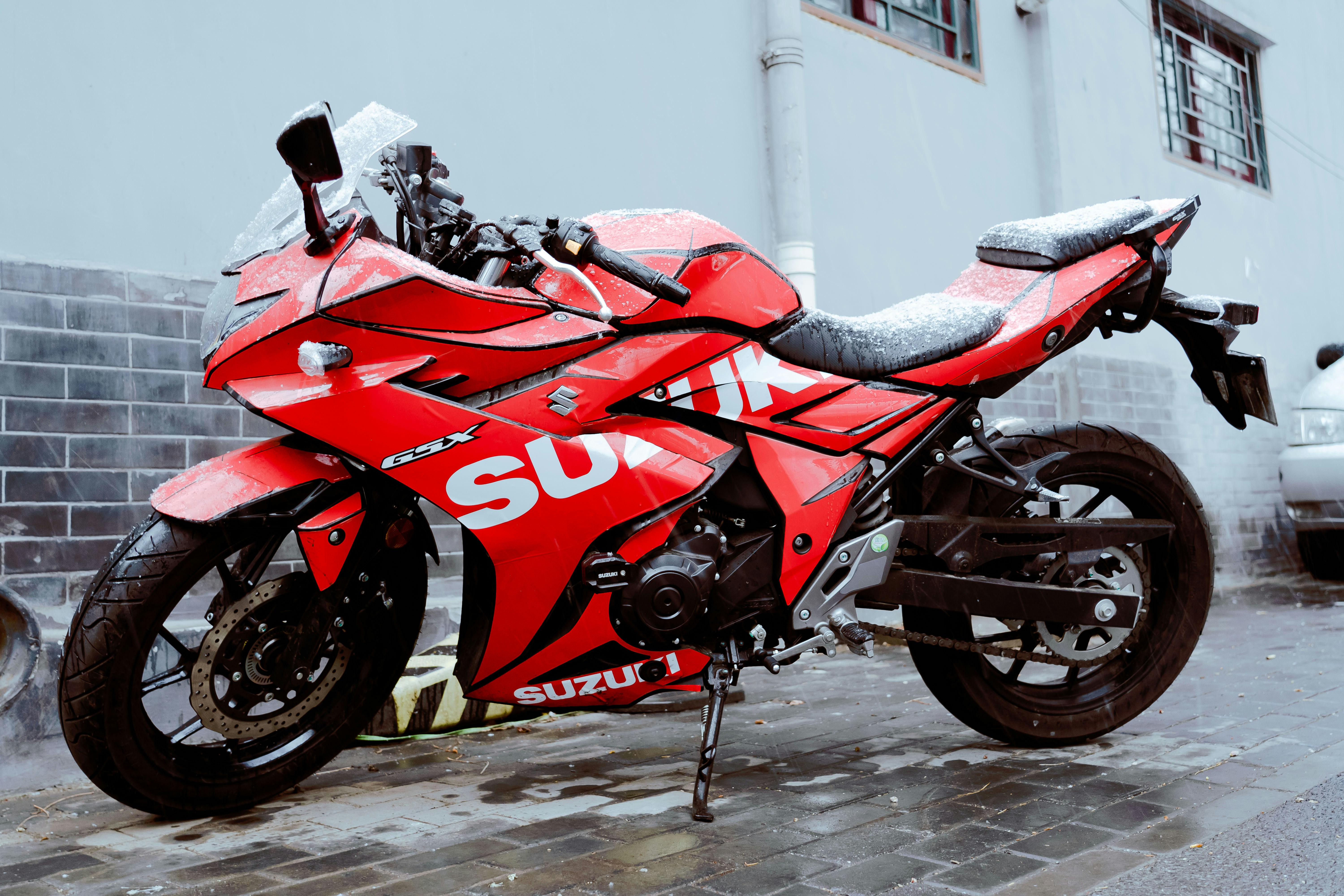 Red motorcycle with bold decals parked against a gray urban wall.