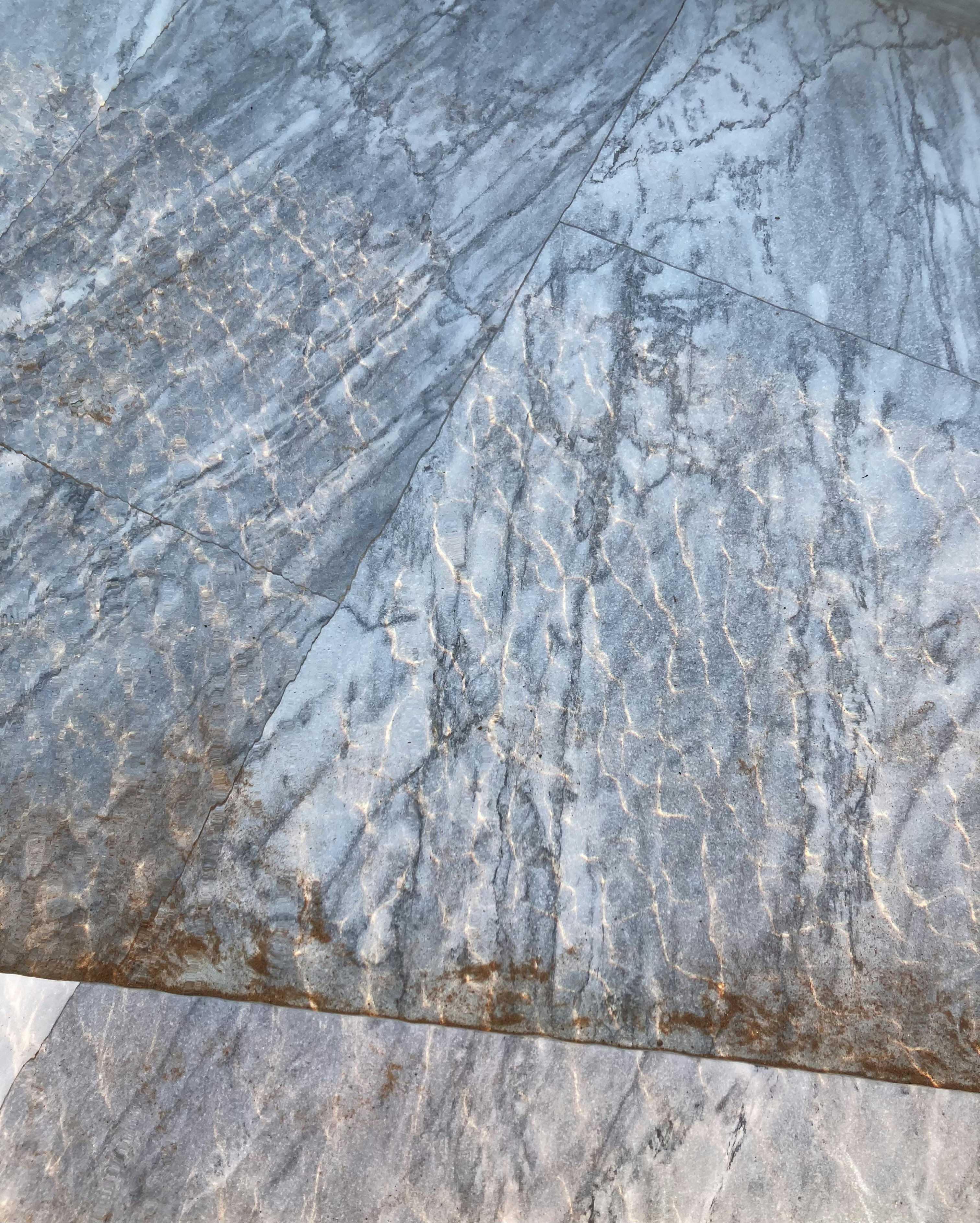 Intricate patterns of gray marble flooring showcasing natural veining and texture. The light reflects subtly, enhancing the stone's organic beauty.