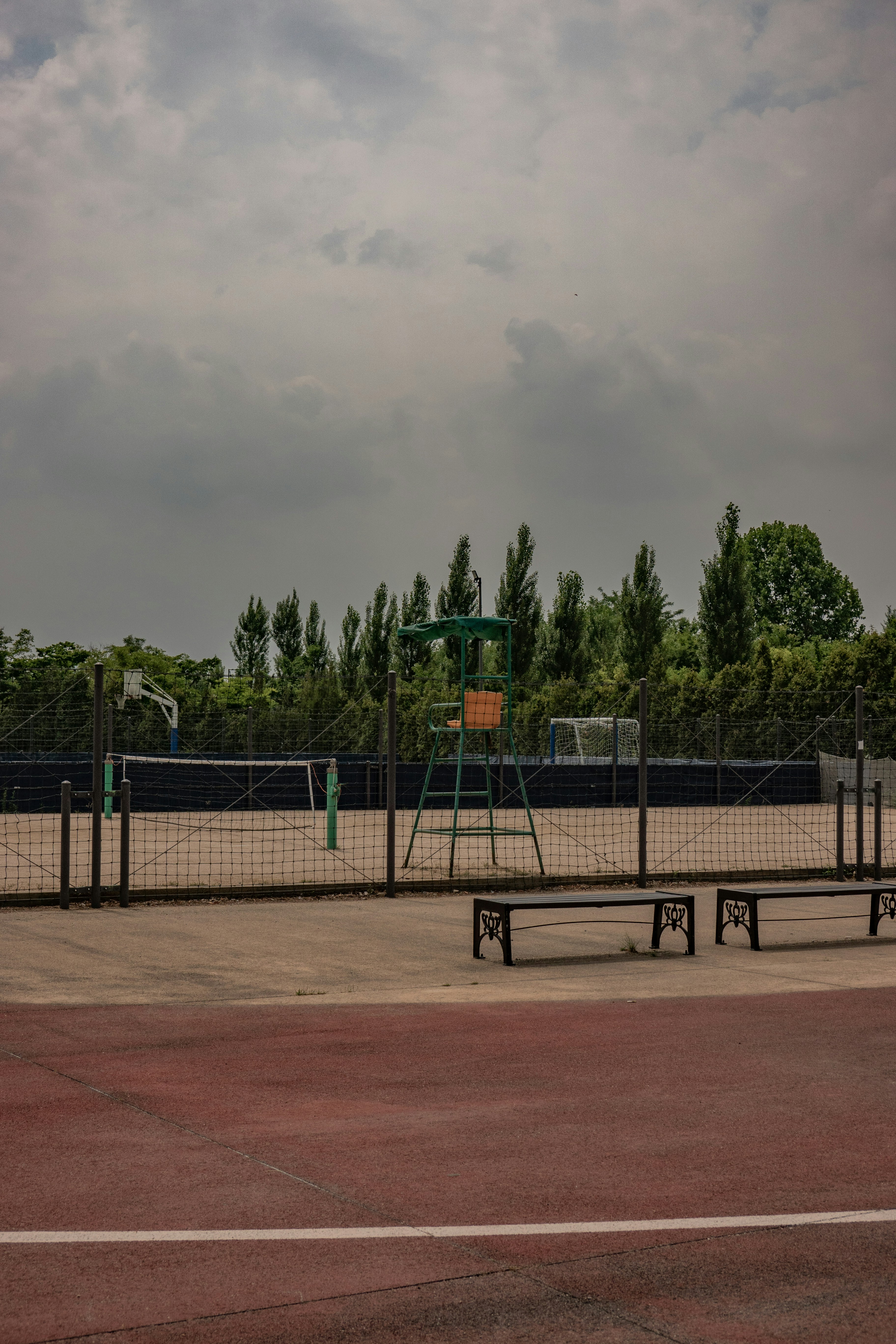 Overcast Courtwatch: The Green Lifeguard Chair Anchors a Quiet Outdoor Arena
