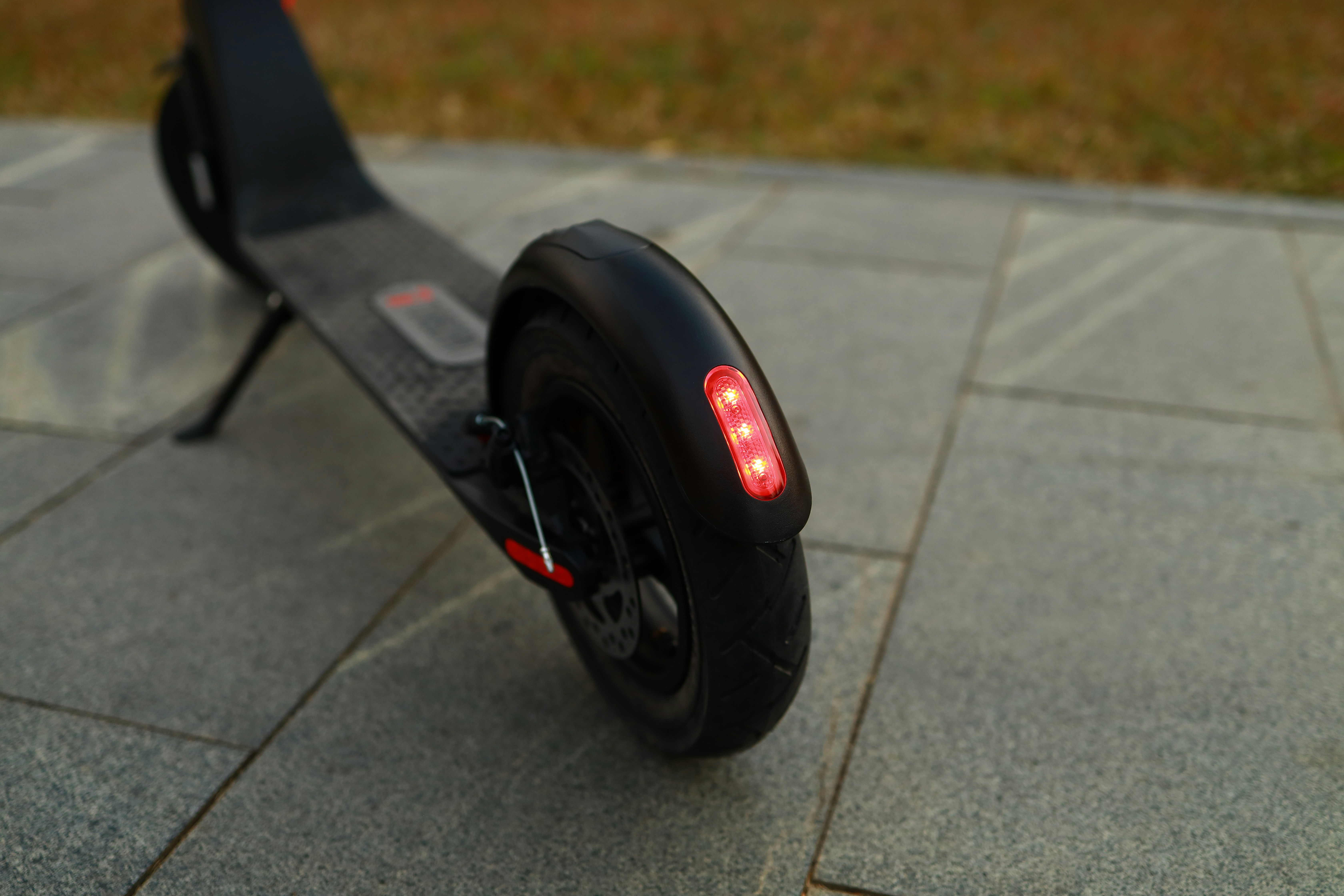 Rear-illuminated ride: close-up of a glowing tail light on a parked electric scooter