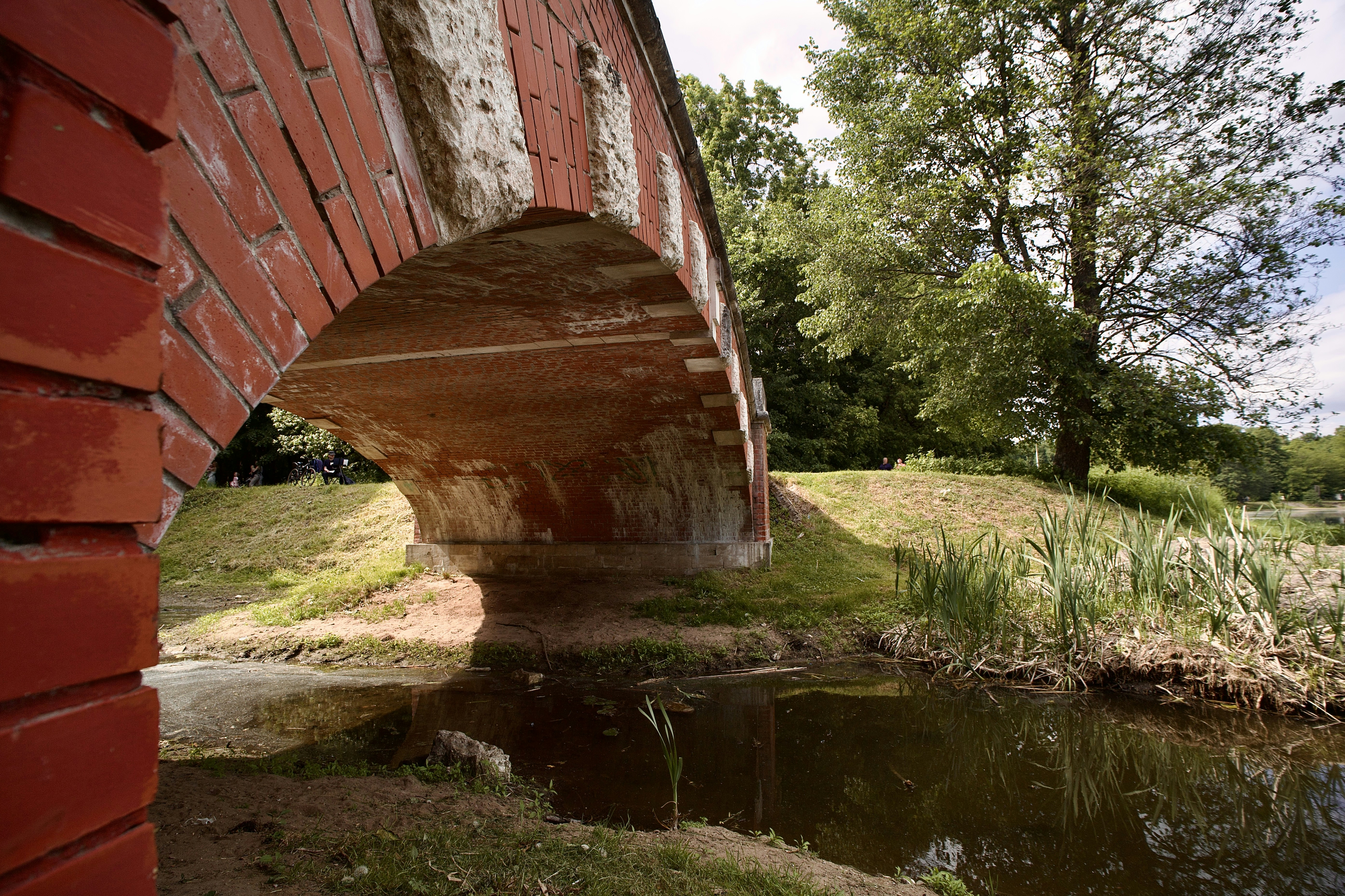 Red Brick Arch Framing a Quiet Creek in Dappled Noon Light