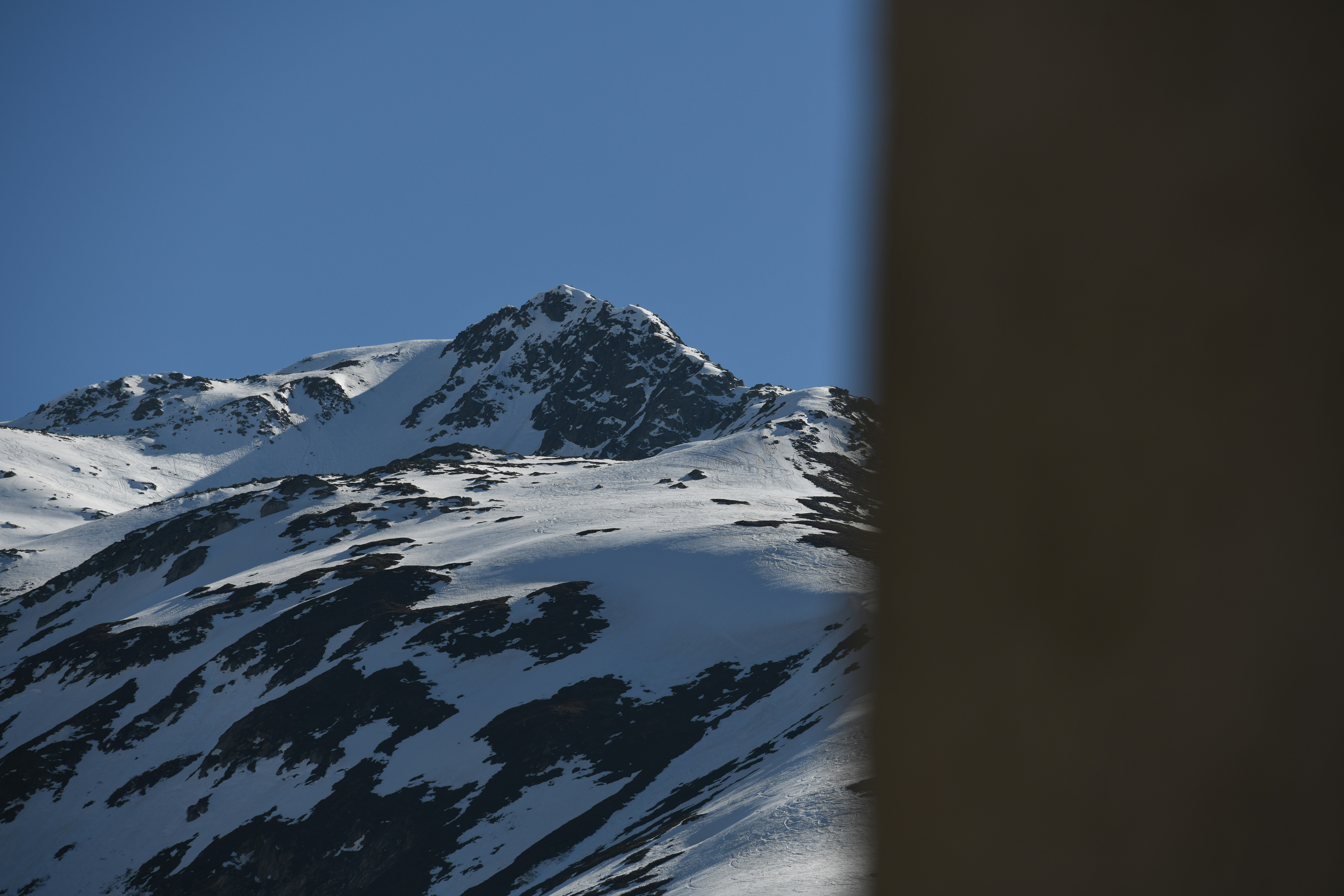 Blue Silence on the Snowcap: Alpine Summit Framed by a Shadowed Edge