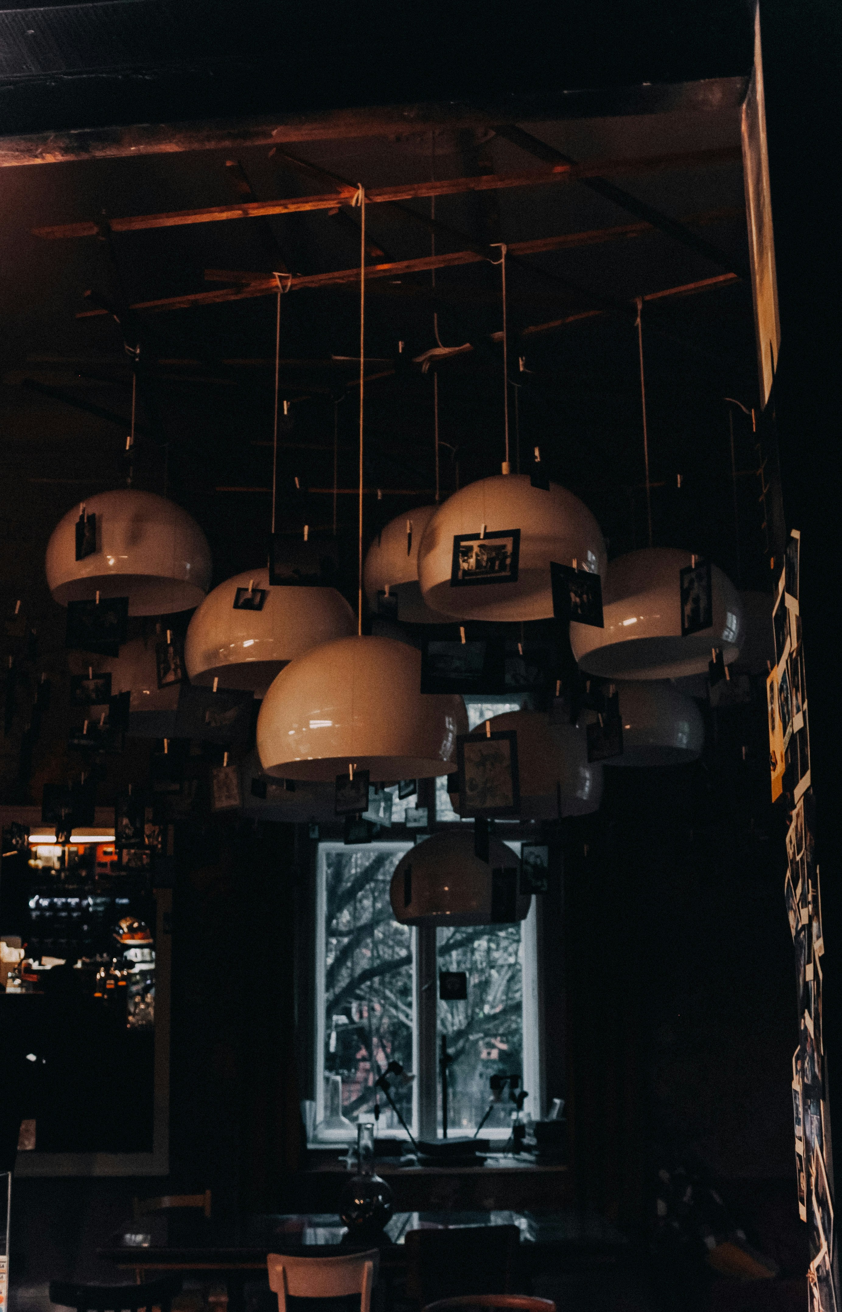 Hanging pendant lights adorned with vintage photographs create a warm atmosphere in a café, enhancing the nostalgic vibe of the space.