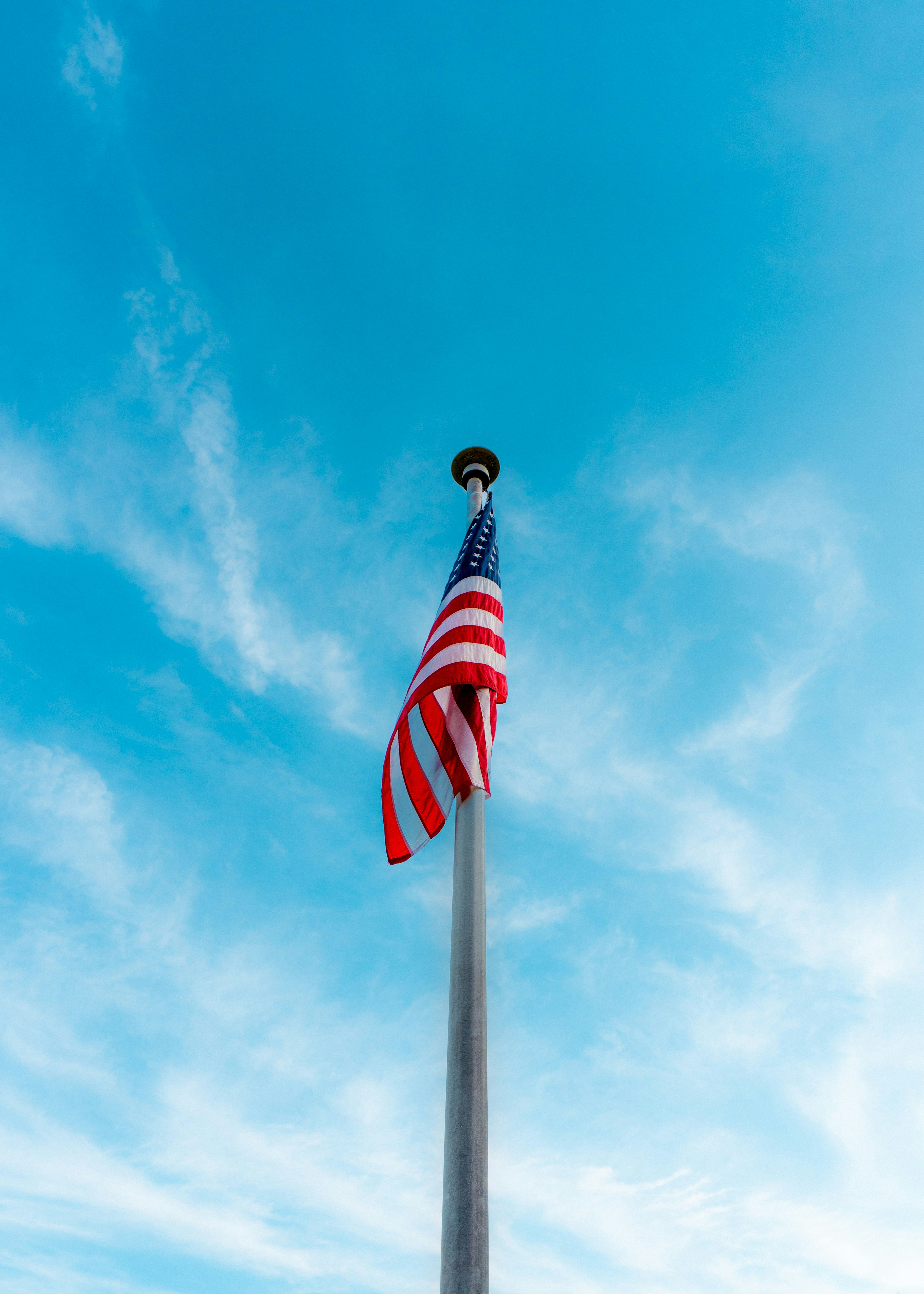 Cerulean Summit: The American Flag Clings to a Skyward Pole