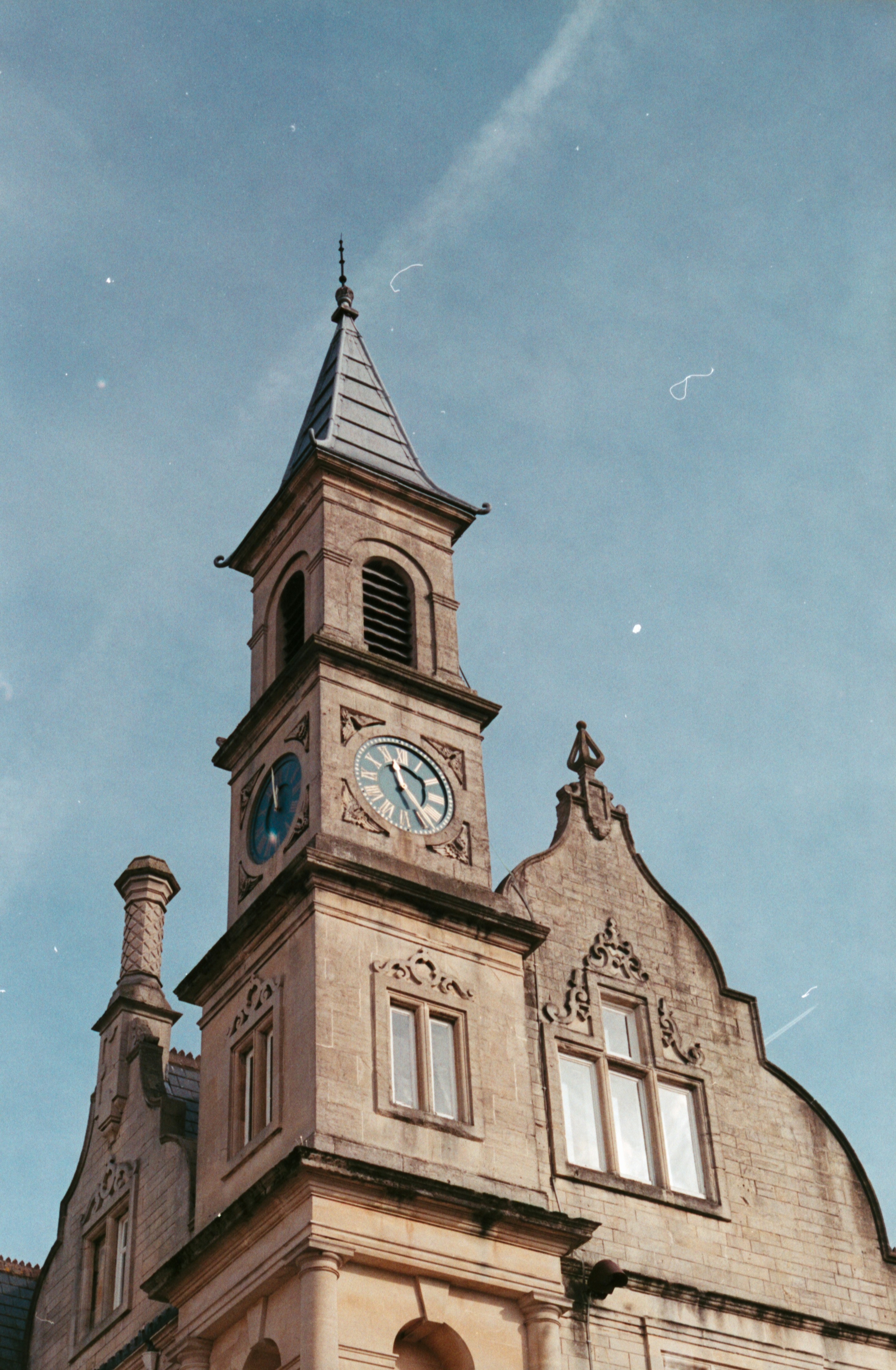 Historic clock tower with ornate architecture and a striking blue clock face against a clear sky.
