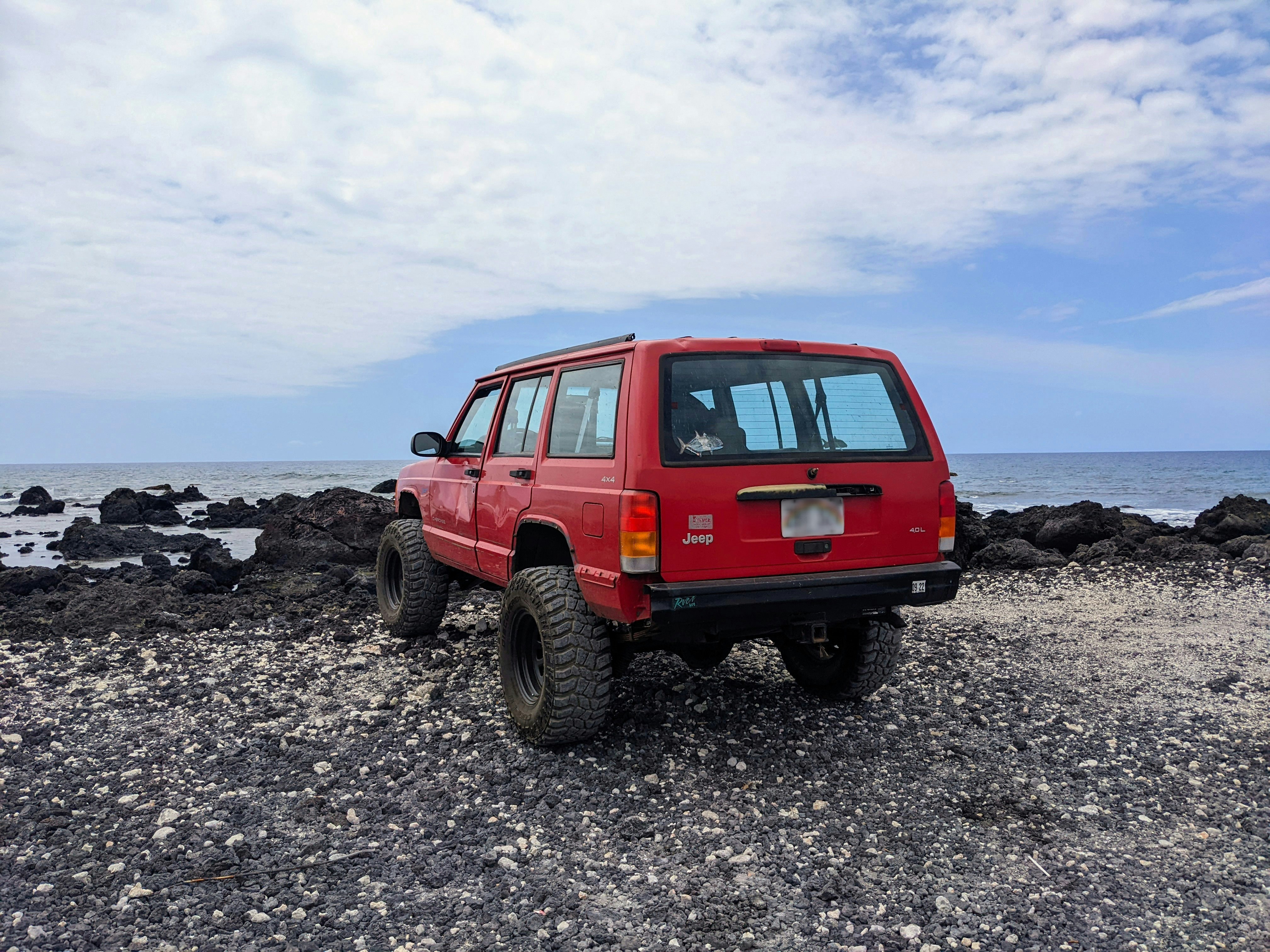 a red car on a rocky beach