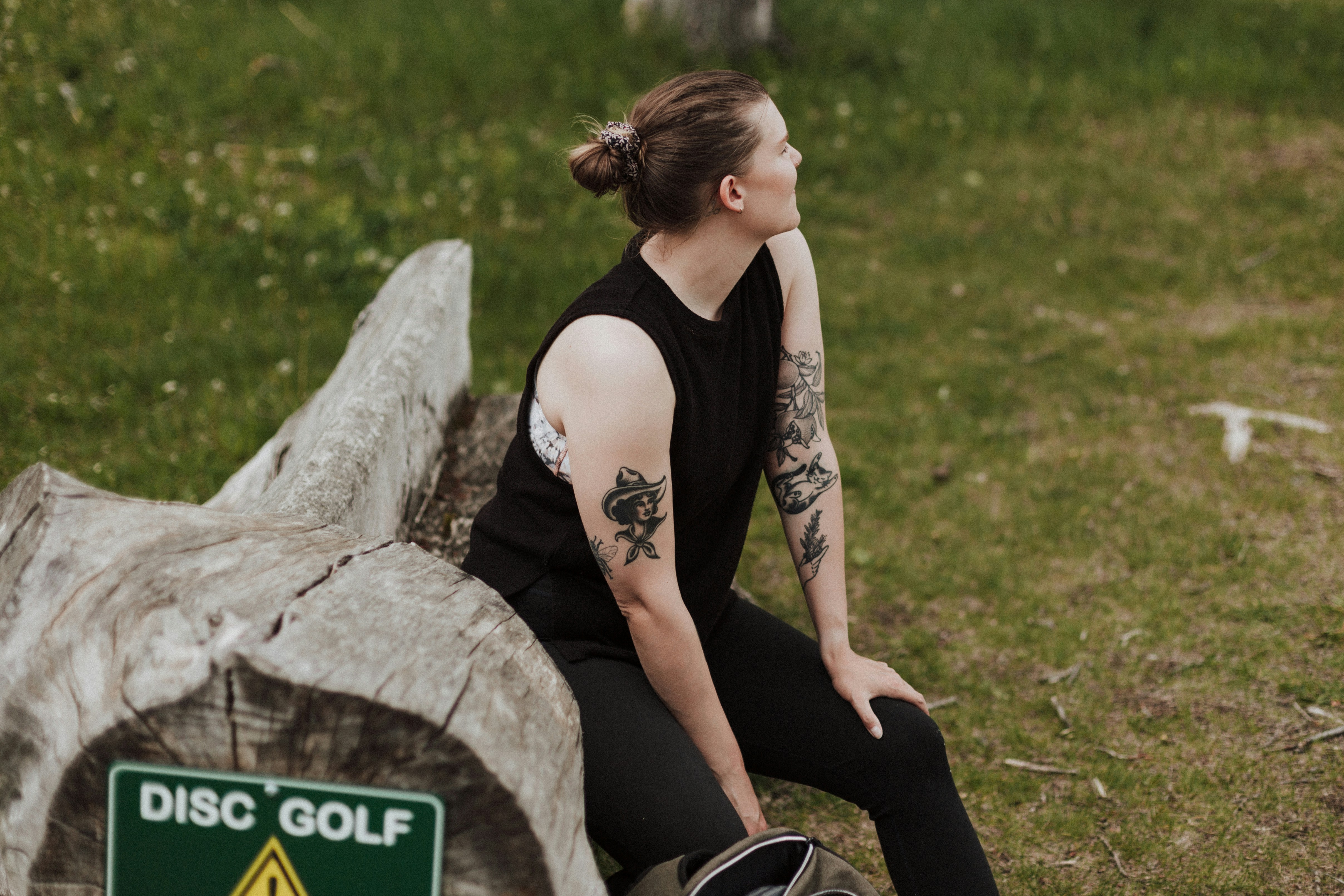 Tattooed Quiet by the Disc Golf Sign: A Moment of Pause in the Park