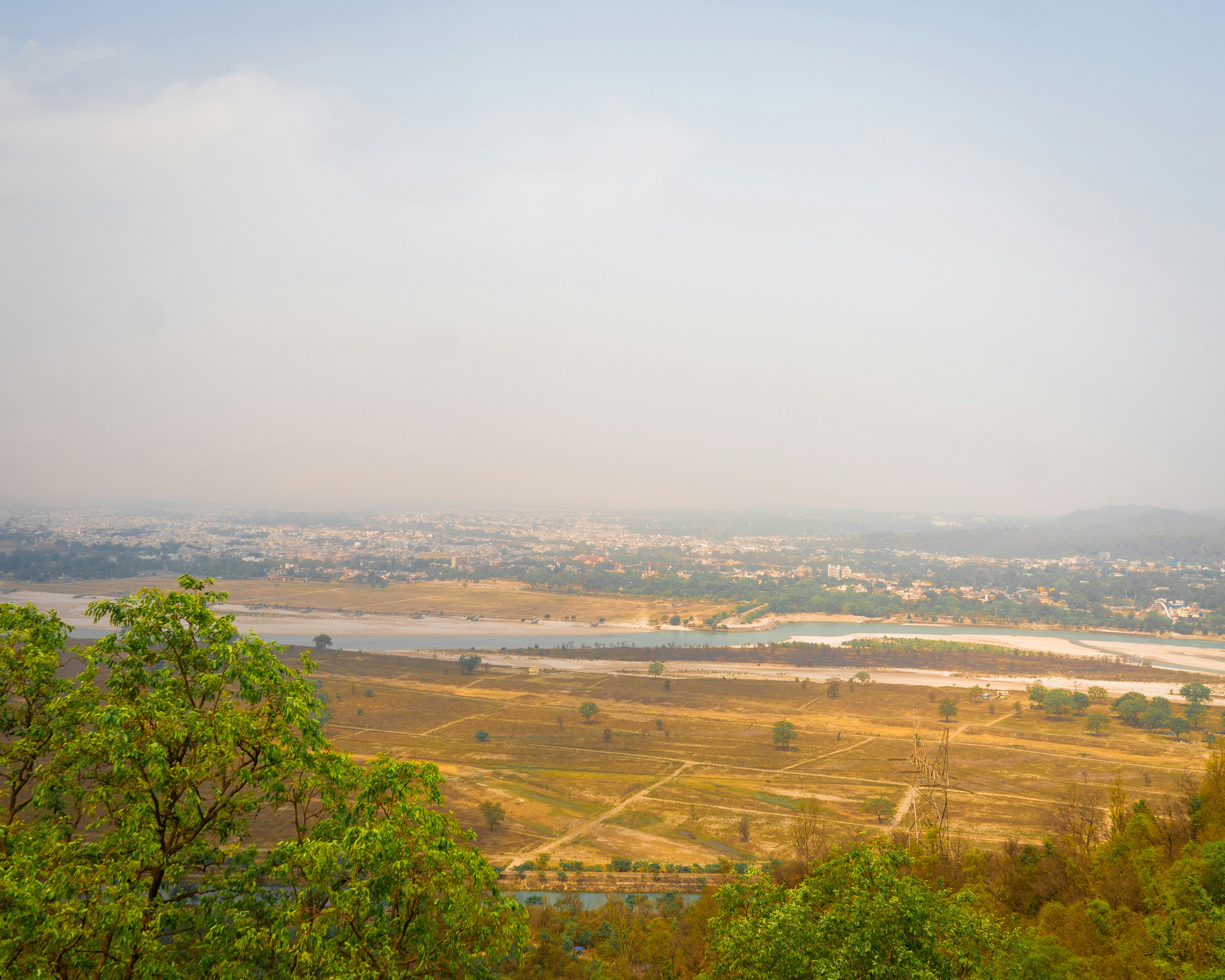 Expansive view of a river winding through a rural landscape under a hazy sky.