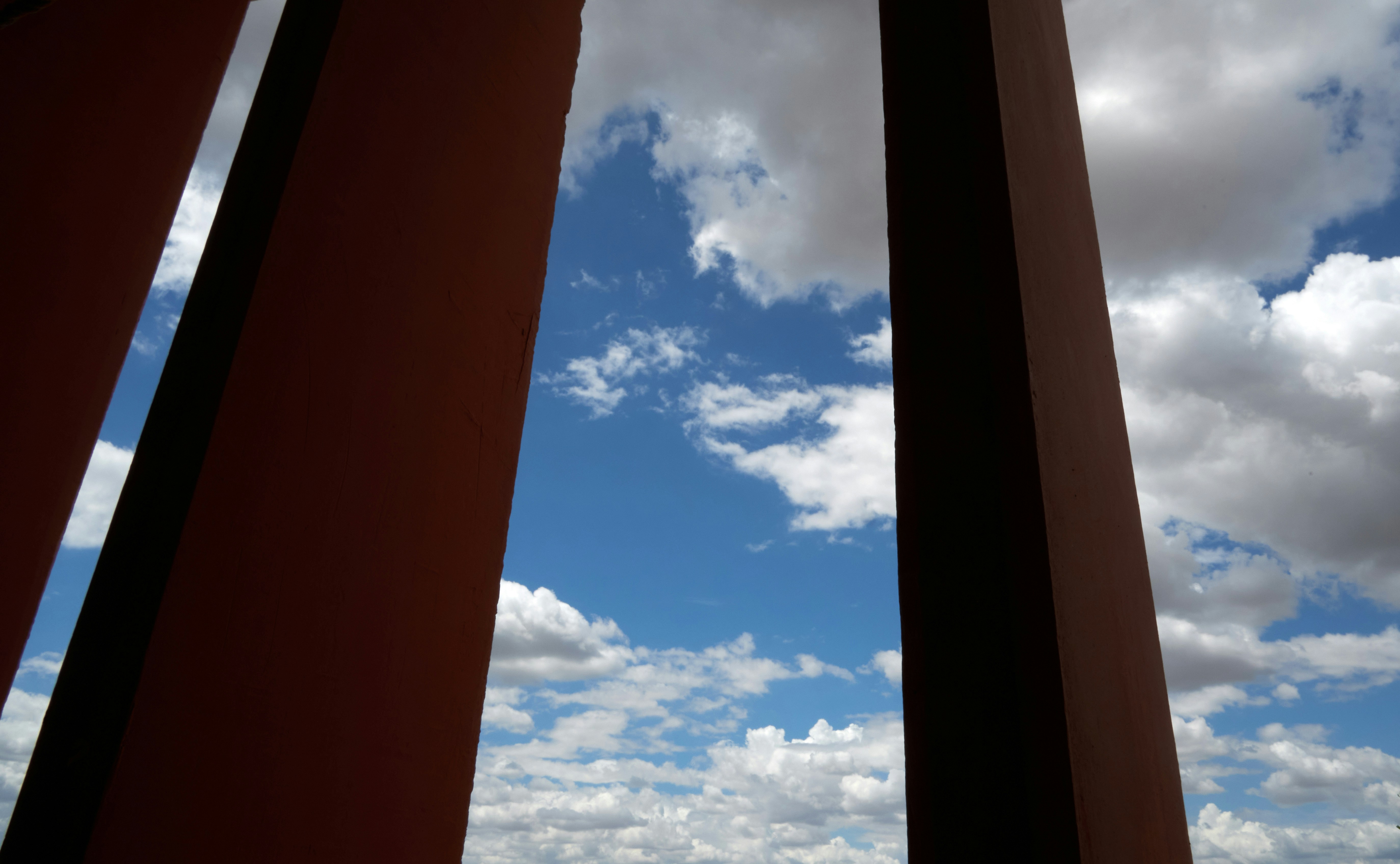 Azure Corridor: Sky Framed by Crimson Columns