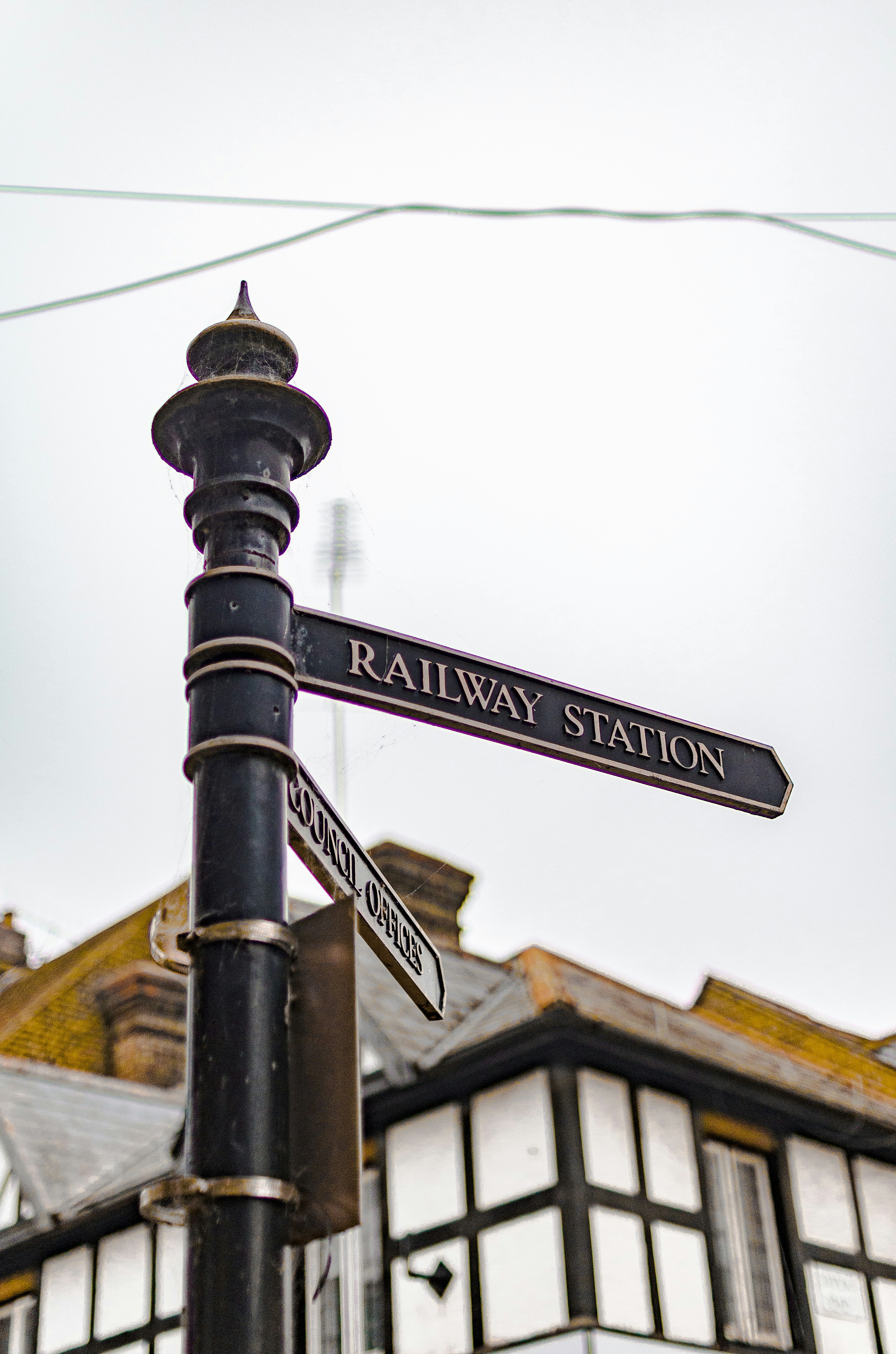 Railway Station Sign on a Weathered Post Framing a Timber-Framed Street
