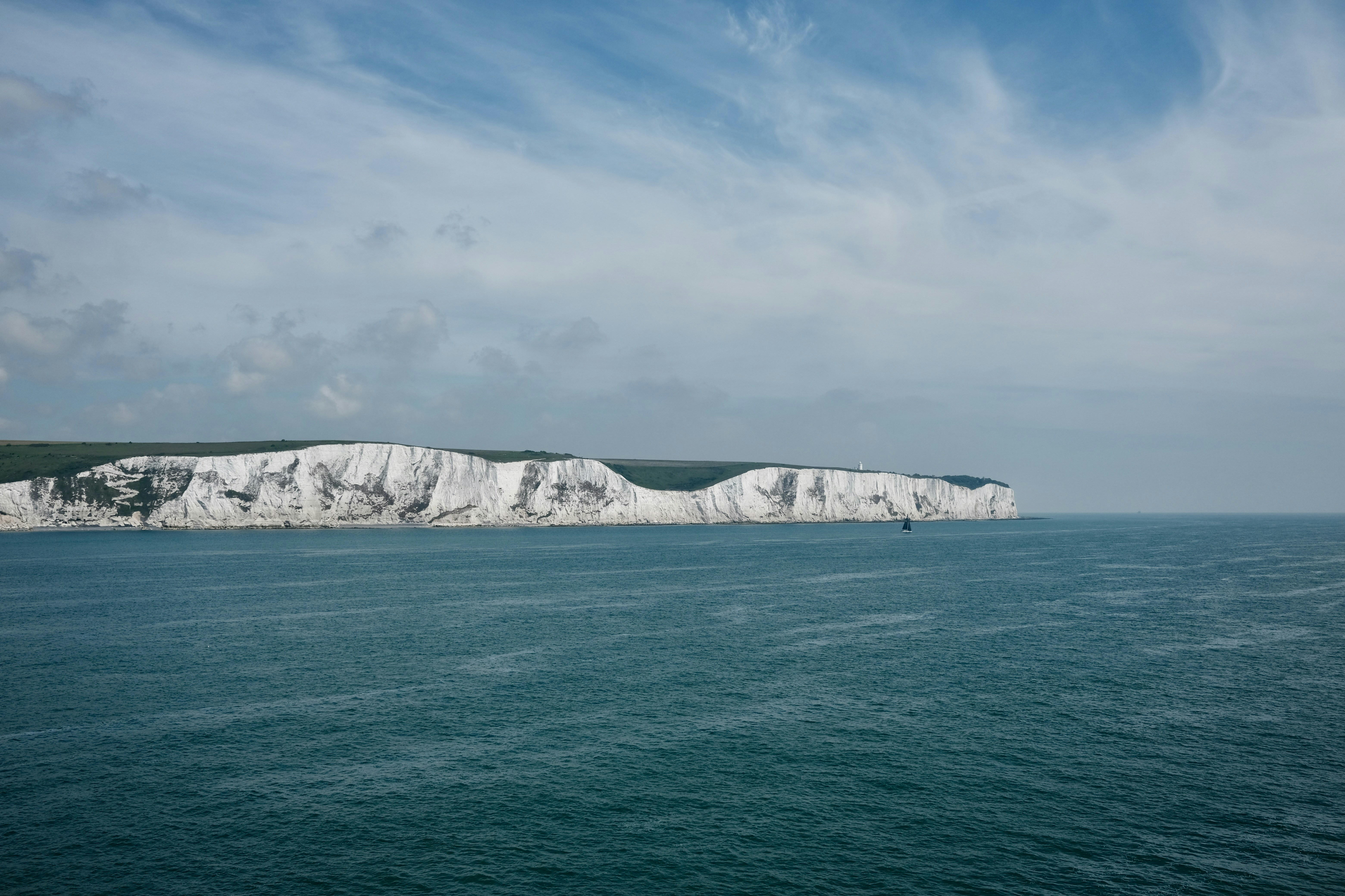 Expansive sea with distant white cliffs under a partly cloudy sky.