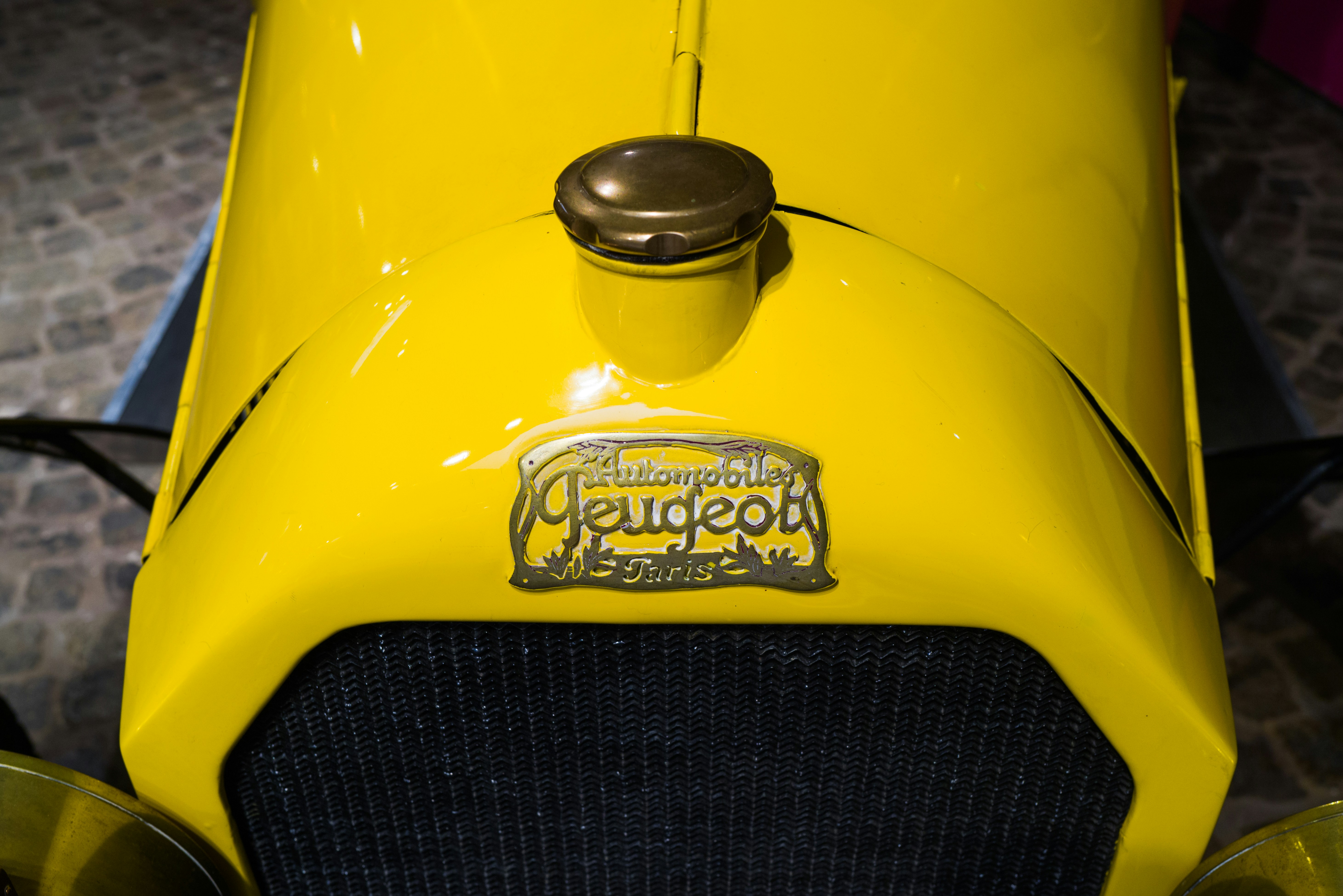 Sunlit Crest on a Yellow Peugeot: A Close-Up of Vintage Character