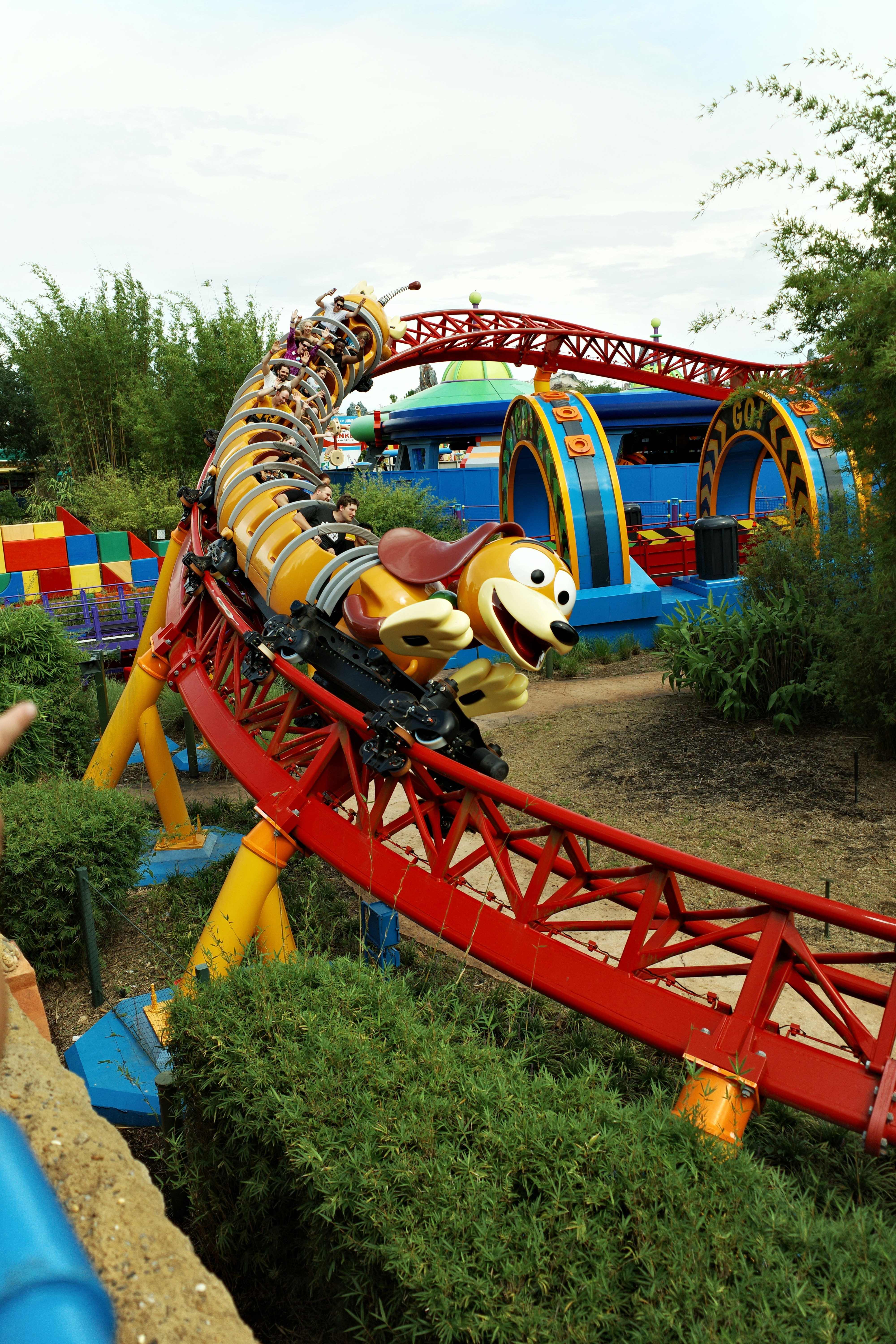 Colorful roller coaster featuring a playful character, surrounded by vibrant scenery and excited riders. The atmosphere reflects the thrill of amusement park adventures.