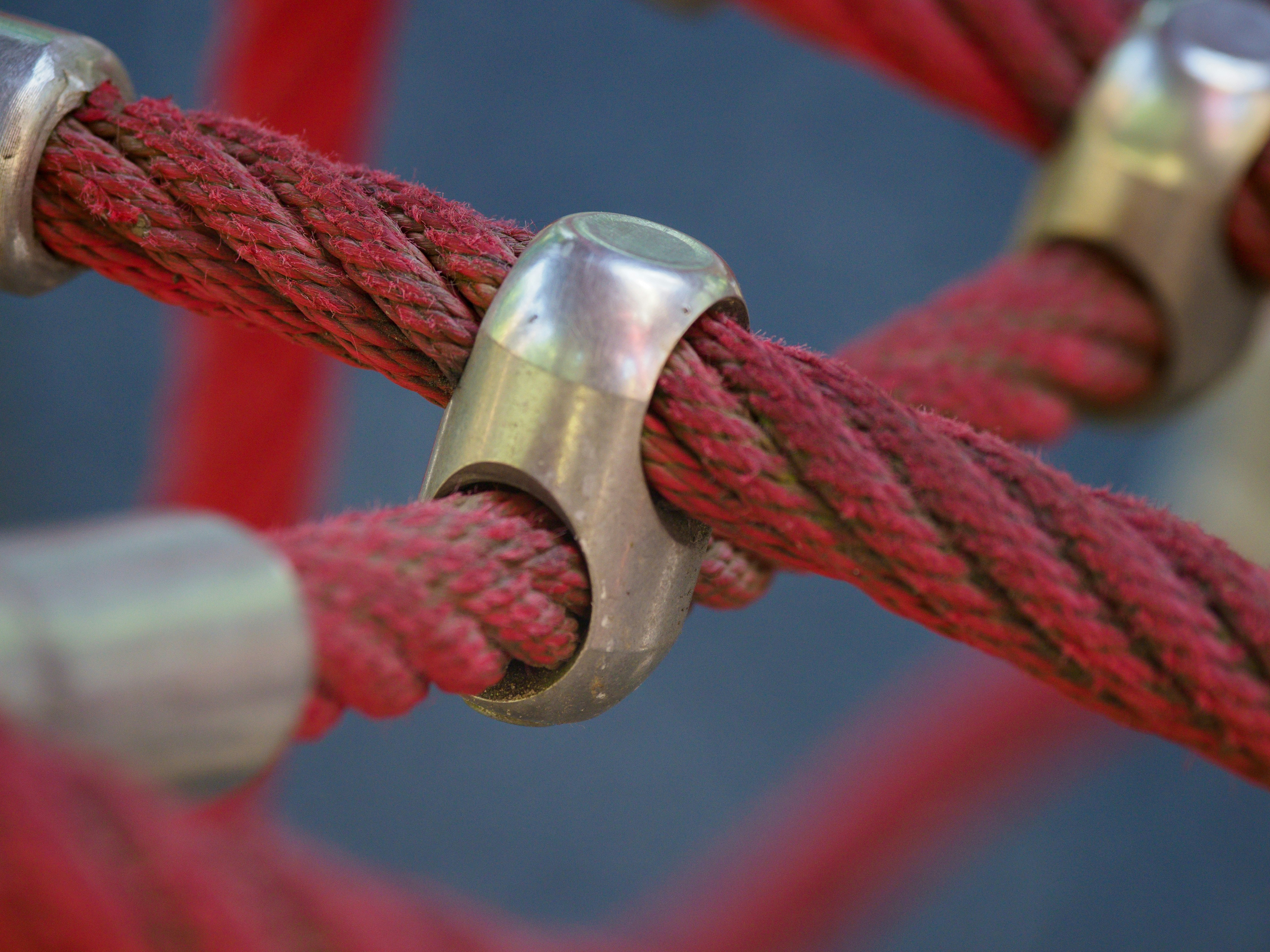 Tethered Threads: A Close-Up of Red Rope and Metal Clamp