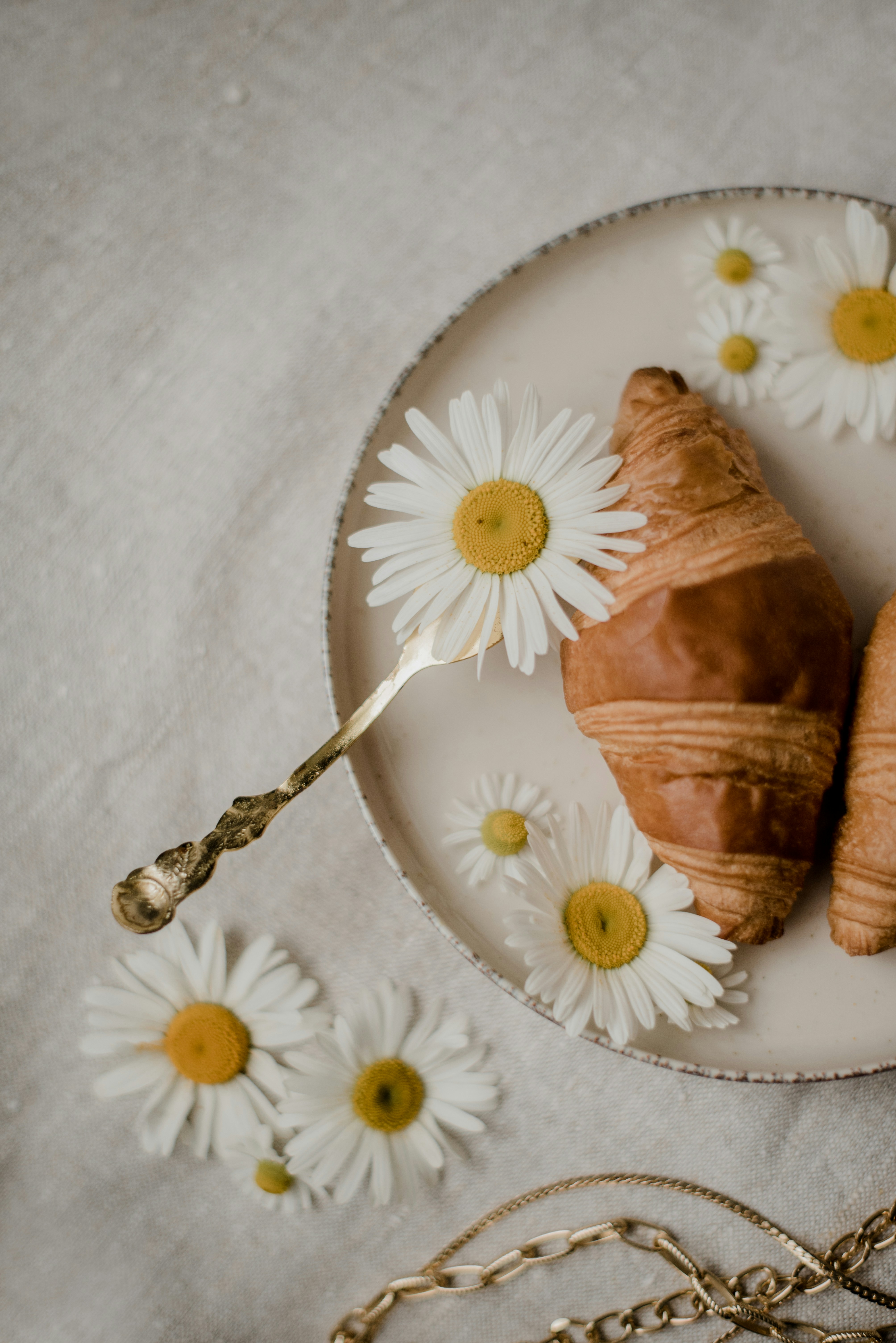 Daisy-Rimmed Morning: Croissant and Floral still life on a pale surface