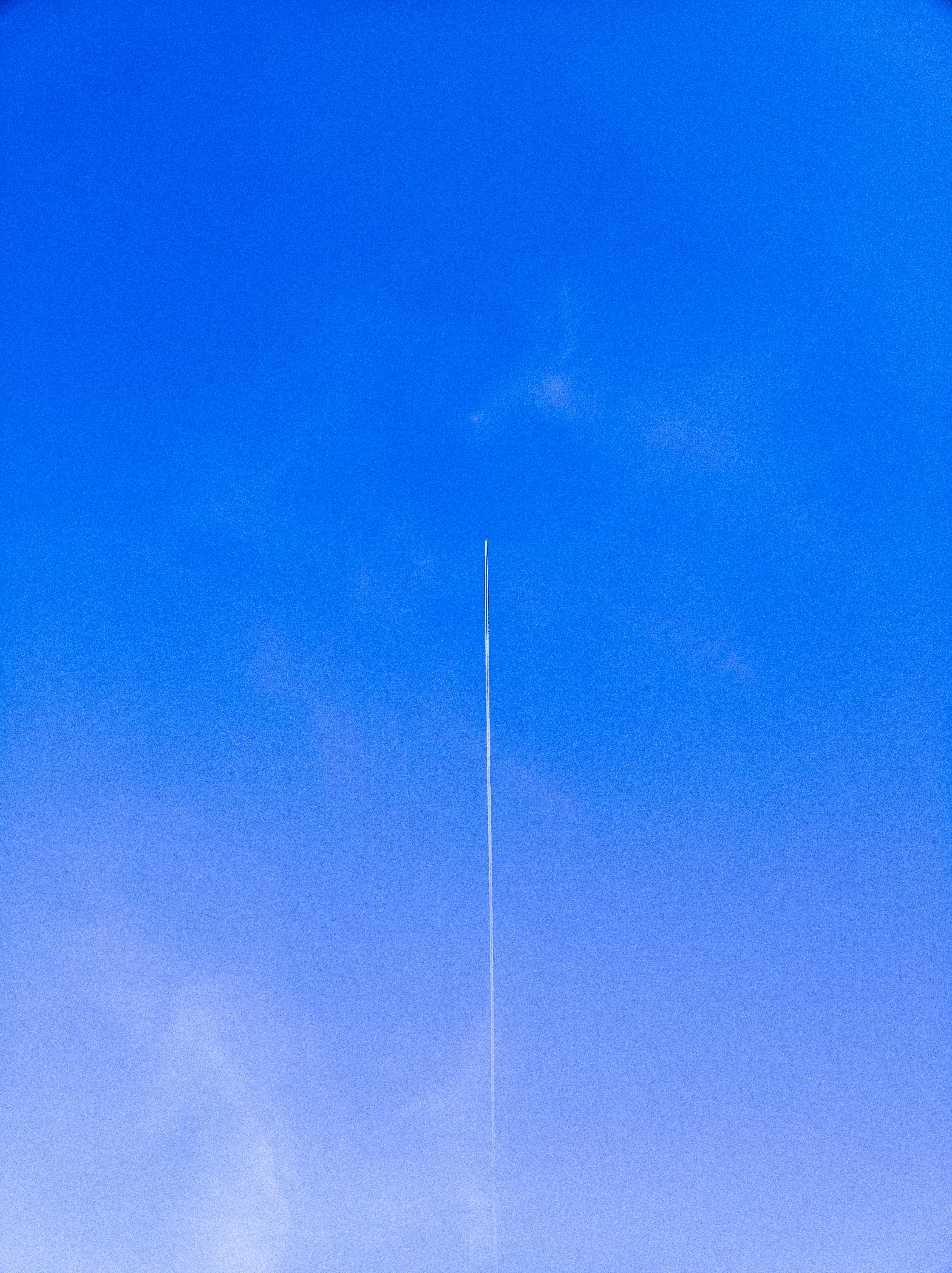 Contrail stretching across a clear blue sky, evoking a sense of movement and freedom.