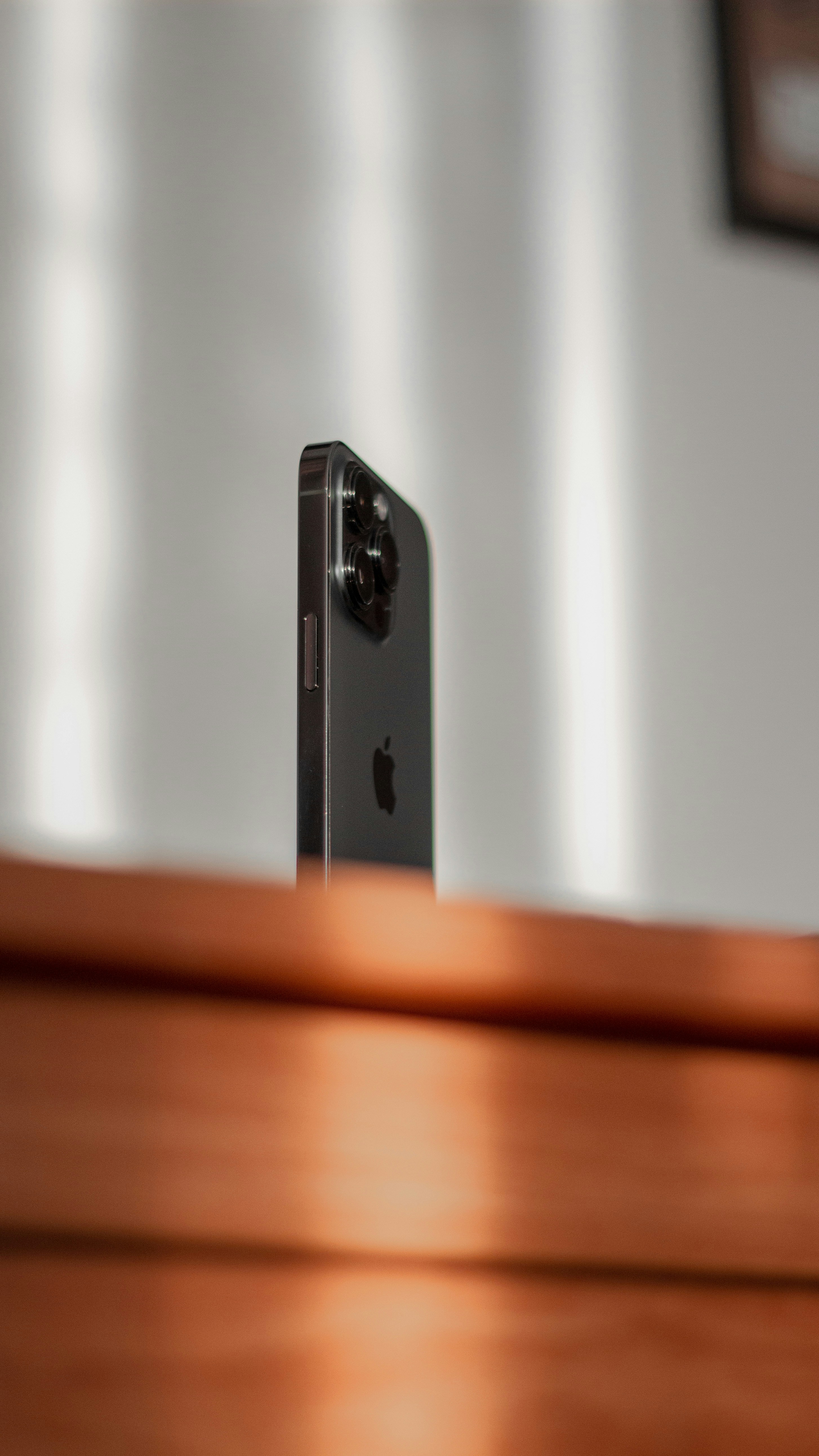 Sleek smartphone positioned on a wooden surface, showcasing its design against a softly lit background.