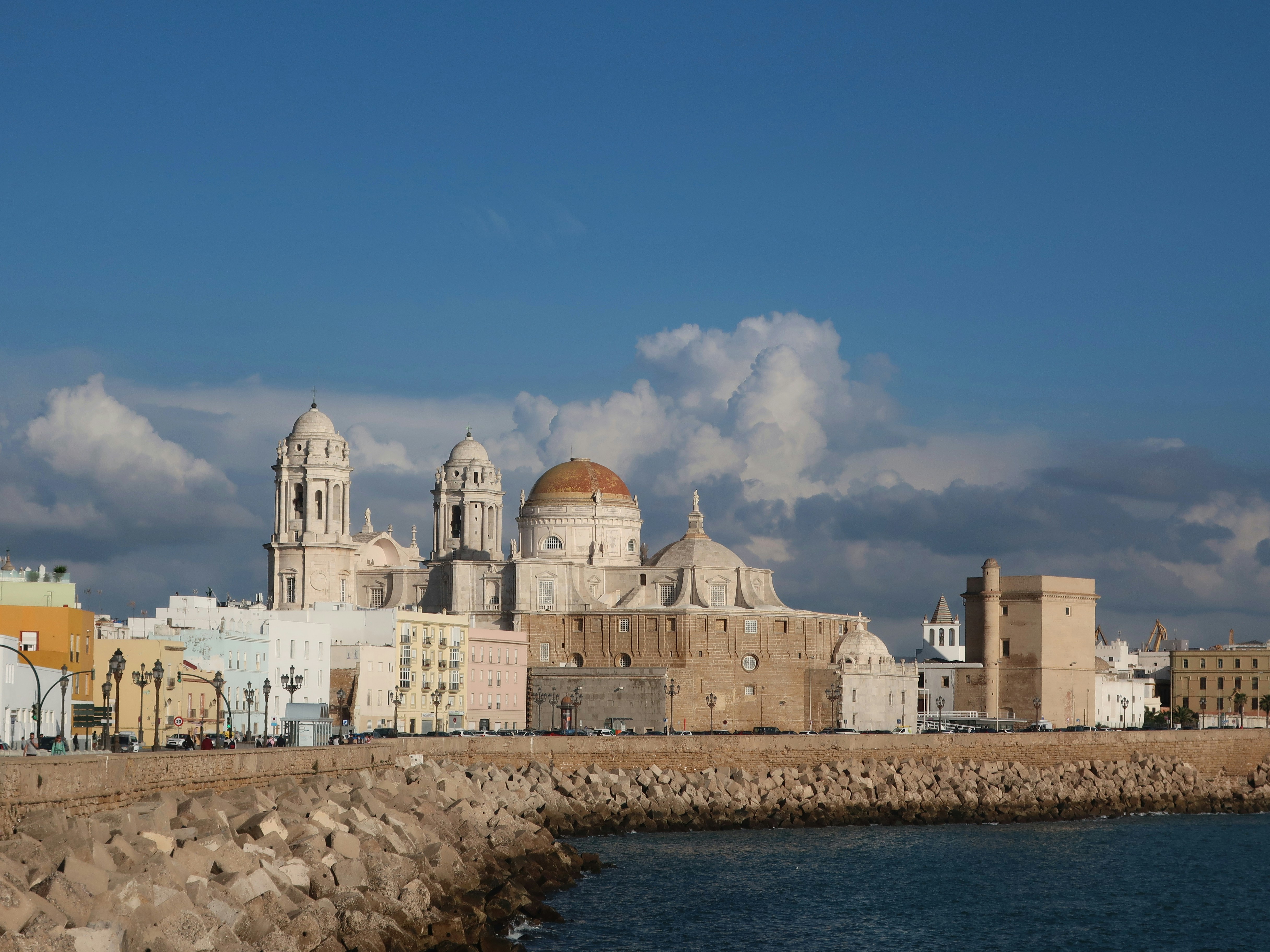 Historic cathedral and coastal buildings under a clear blue sky in Cadiz, Spain.