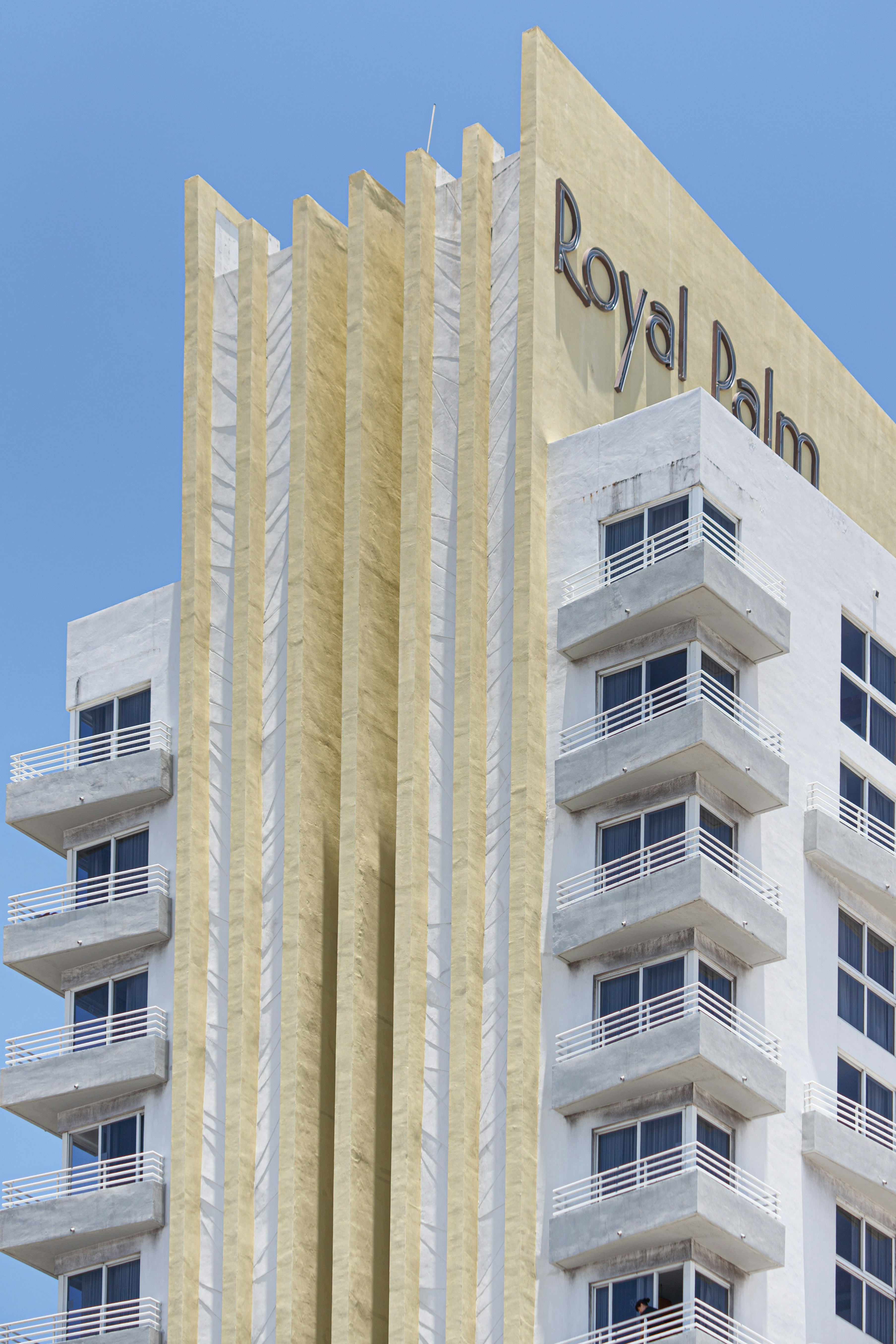 Art Deco-inspired hotel facade with distinct vertical lines and balconies under a clear blue sky.