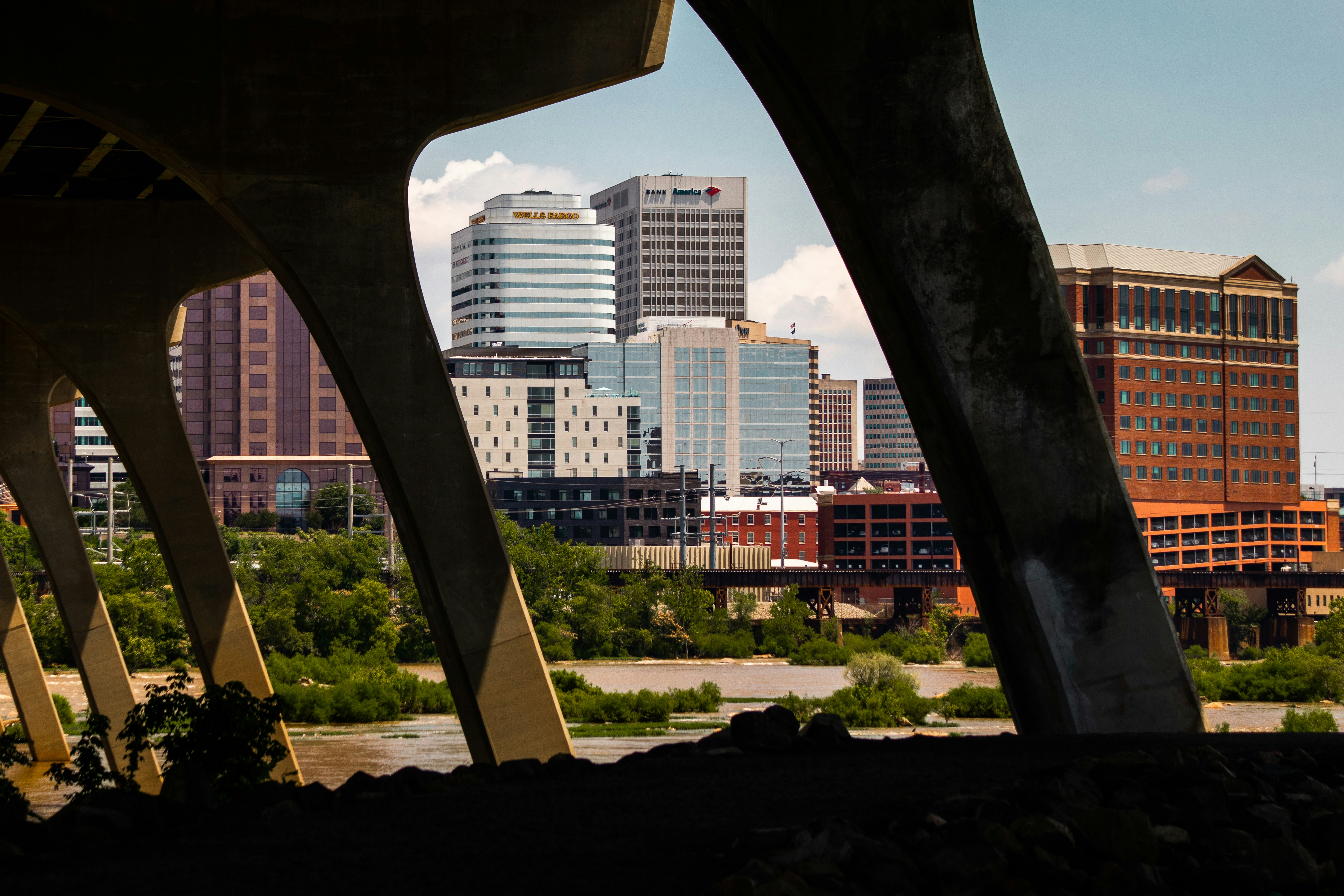 City skyline viewed through the arches of a bridge, with modern buildings under a clear sky.