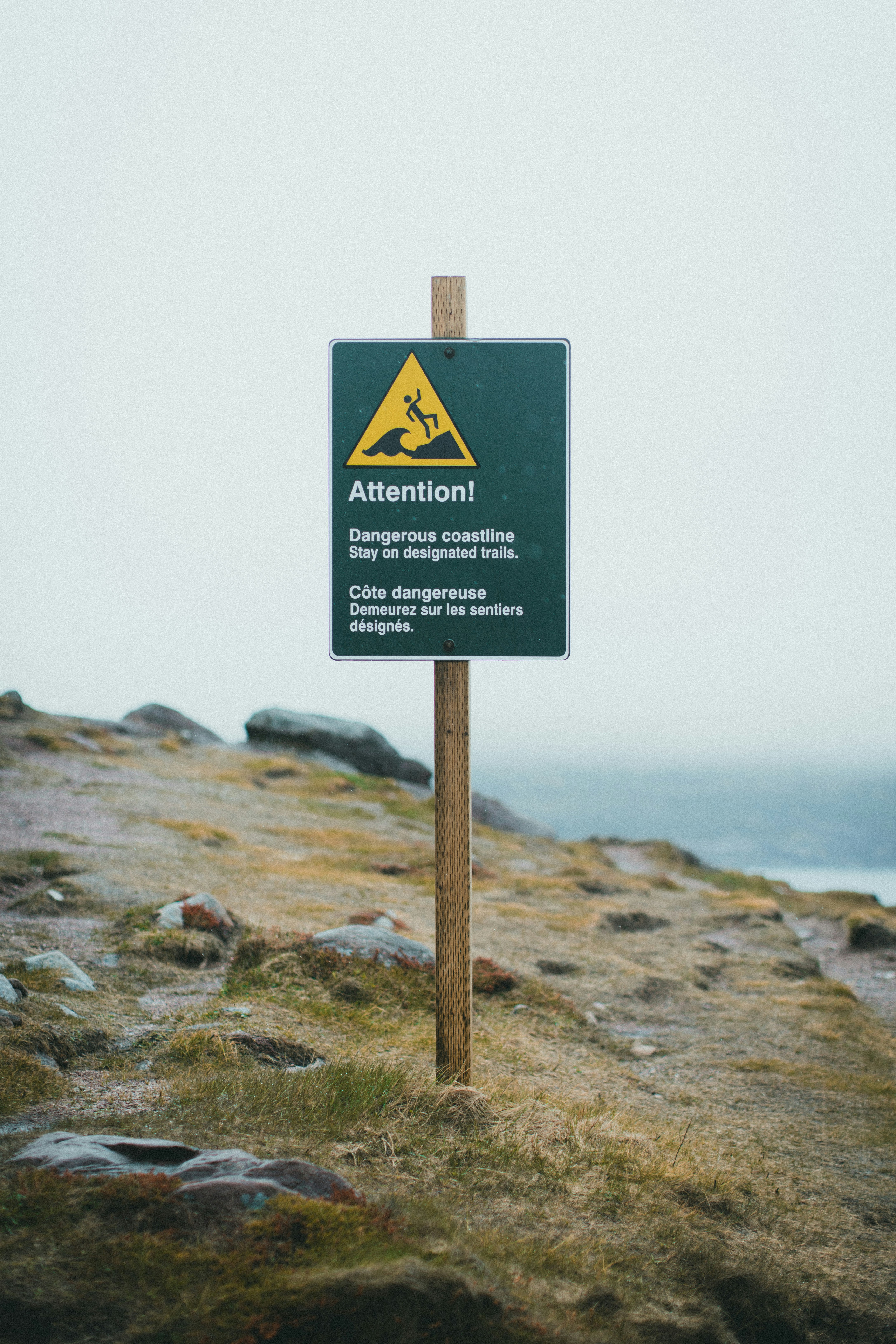 Warning on a windswept cliff: caution sign overlooking the sea