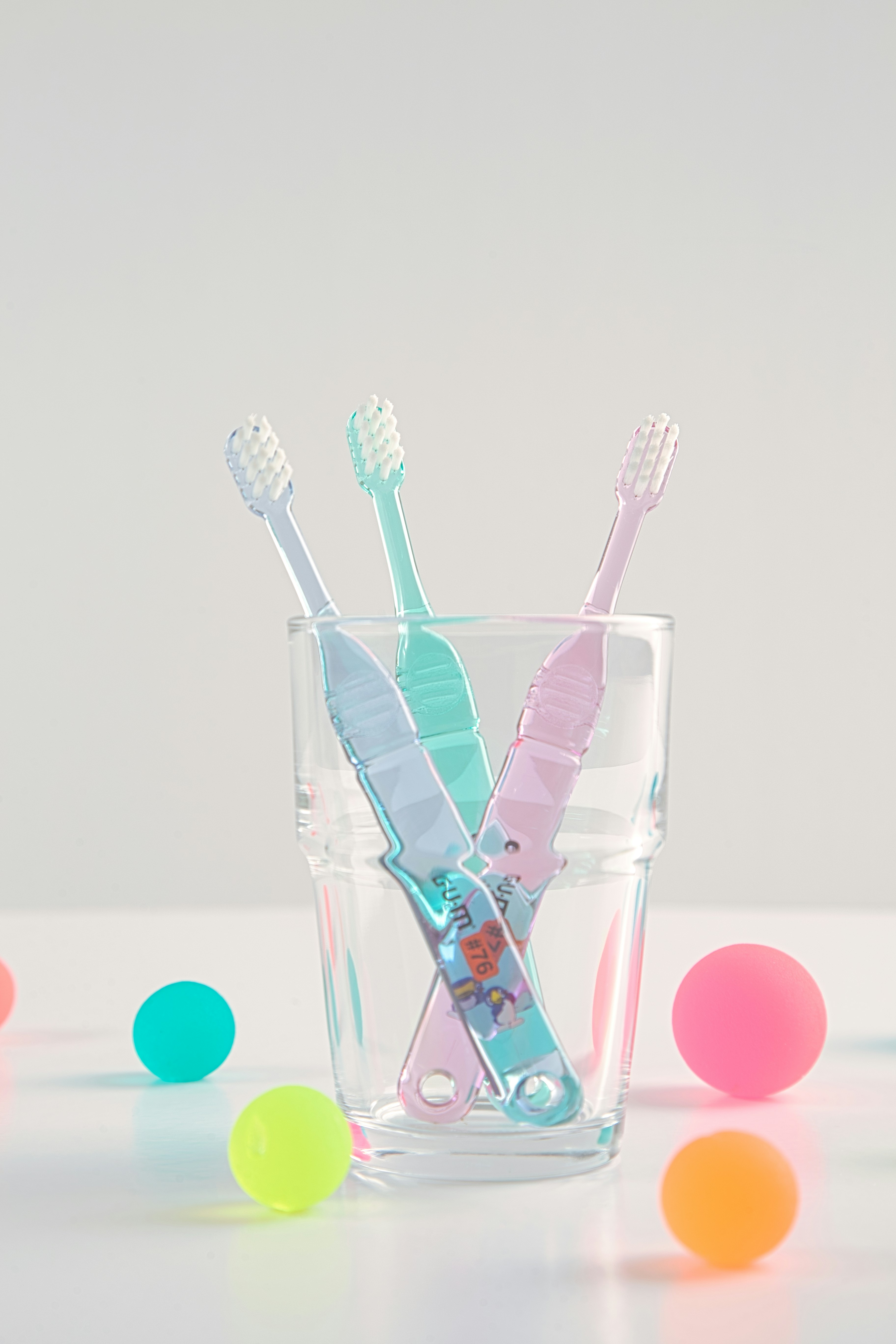 Colorful toothbrushes arranged in a glass, surrounded by vibrant, playful balls. A whimsical take on dental care essentials.