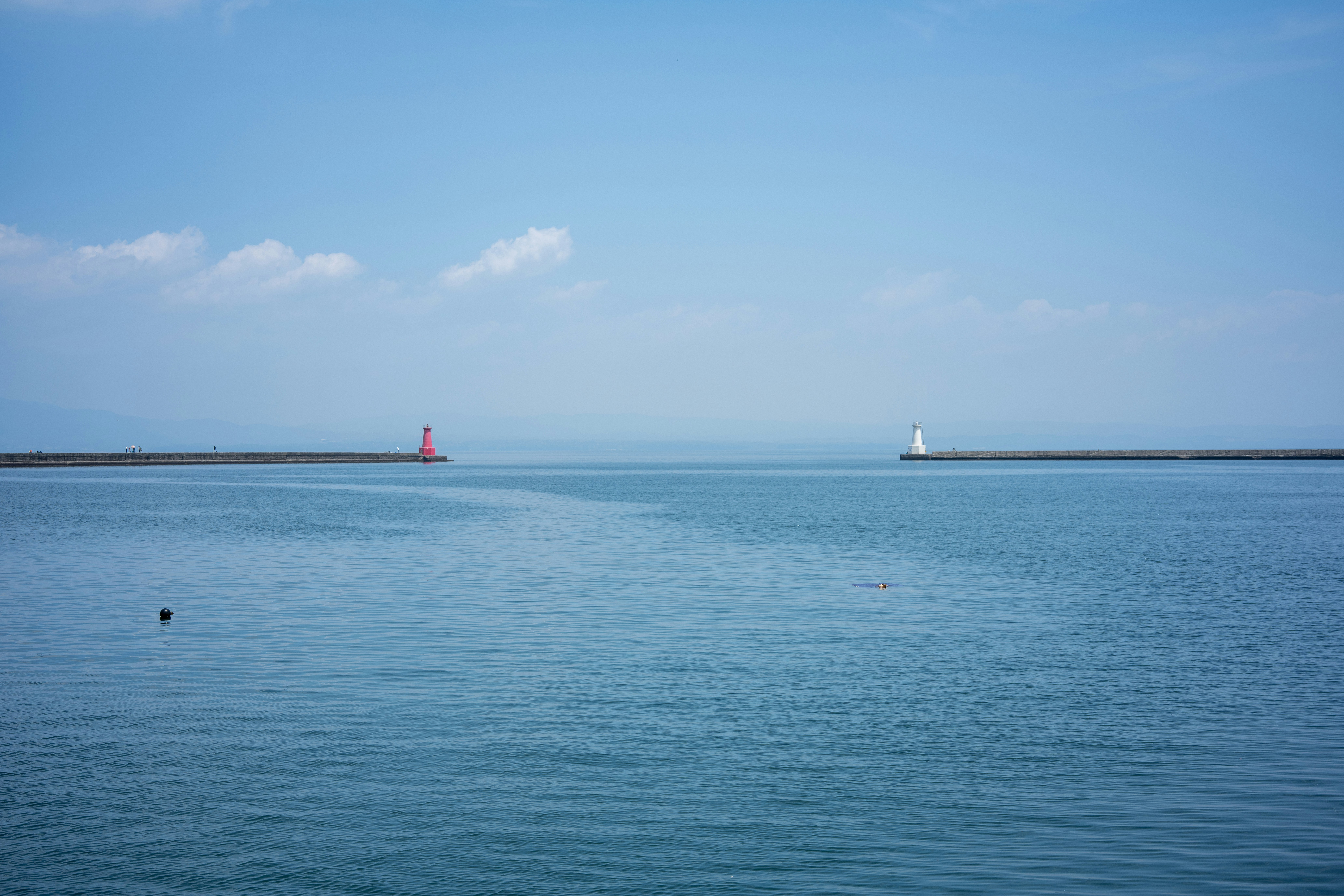 A body of water with a lighthouse in the distance photo – Free Blue ...